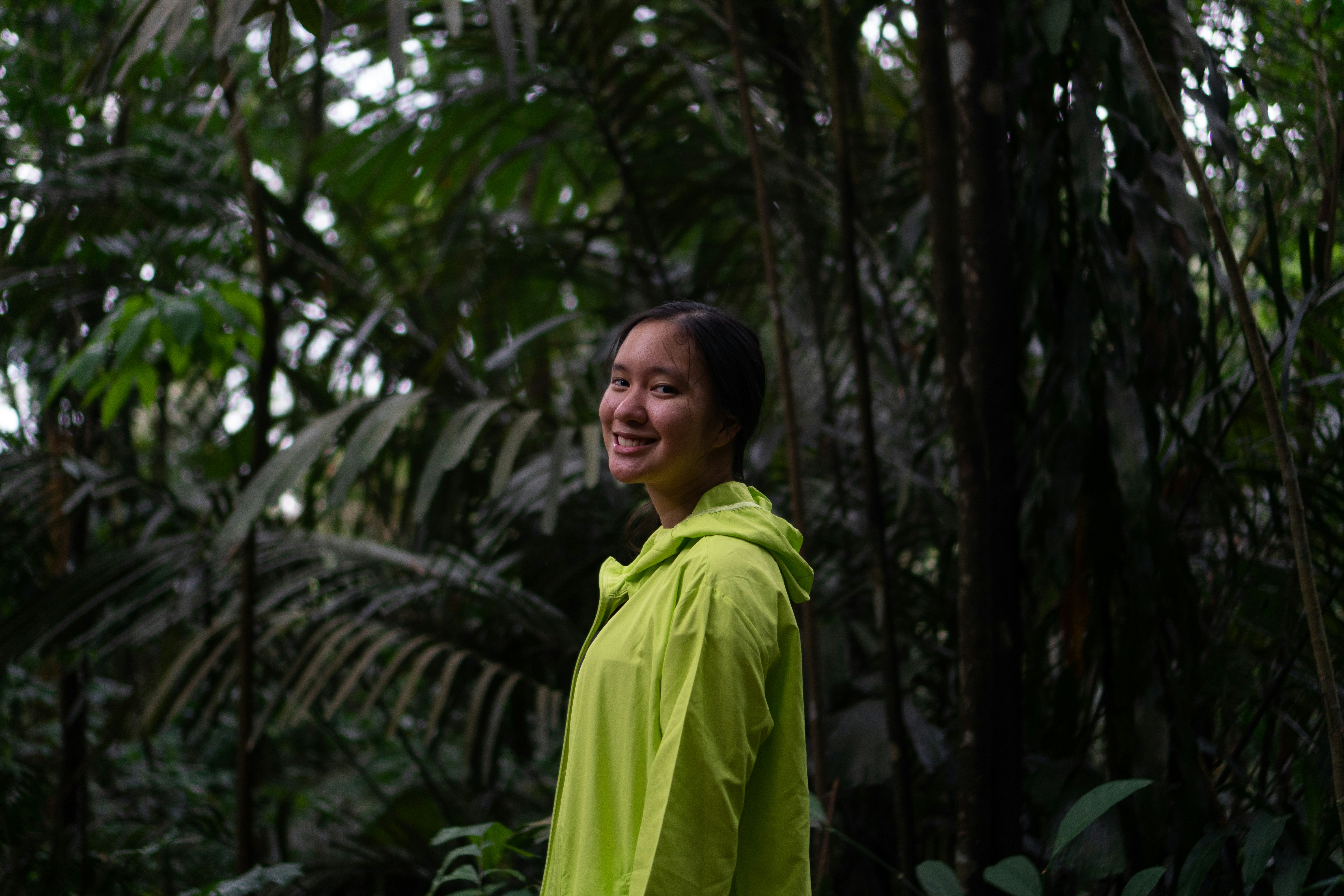 Foto Una mujer con una chaqueta verde parada en un bosque – Imagen ...