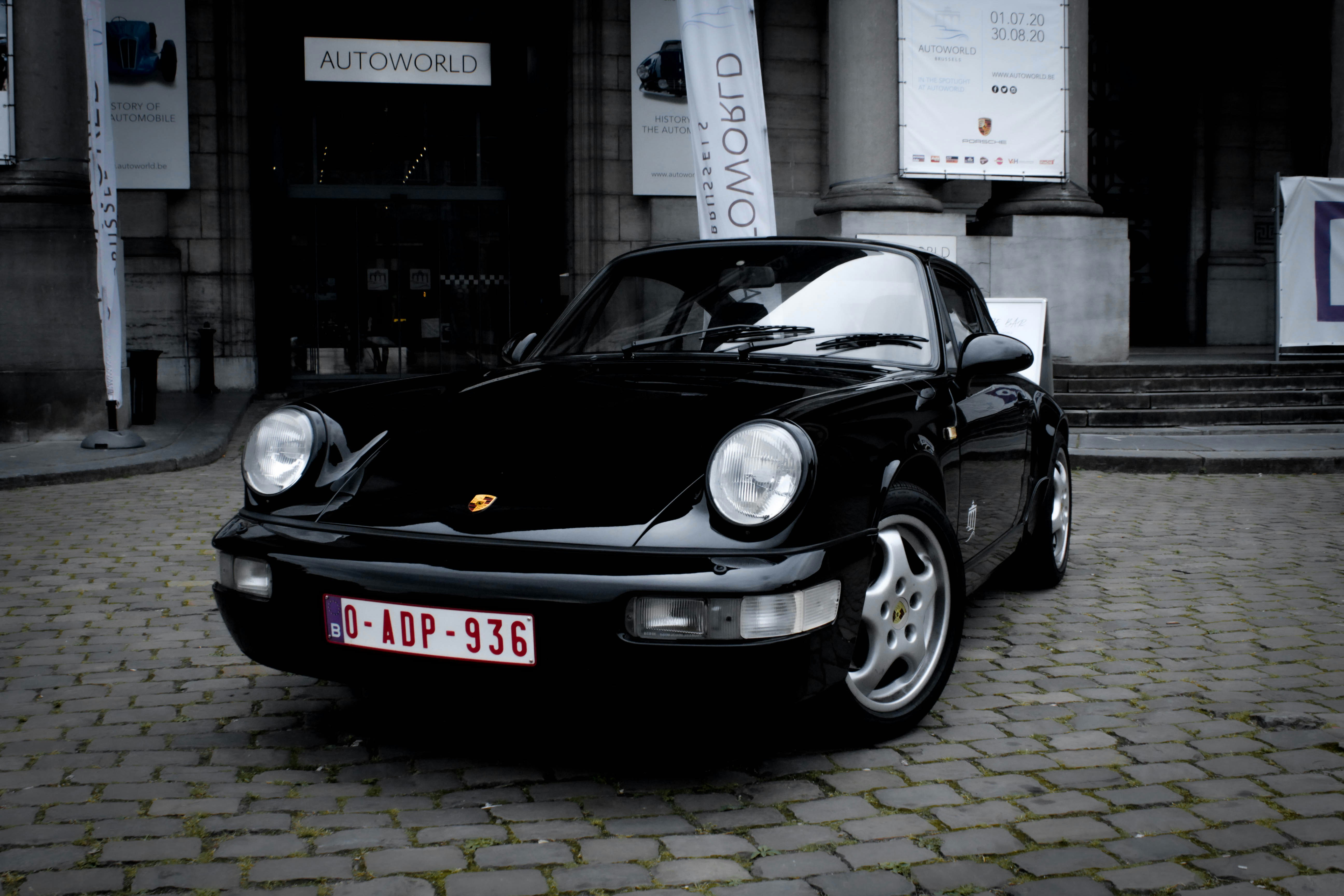Classic black Porsche parked in front of a historic building, showcasing its iconic design and sleek lines.