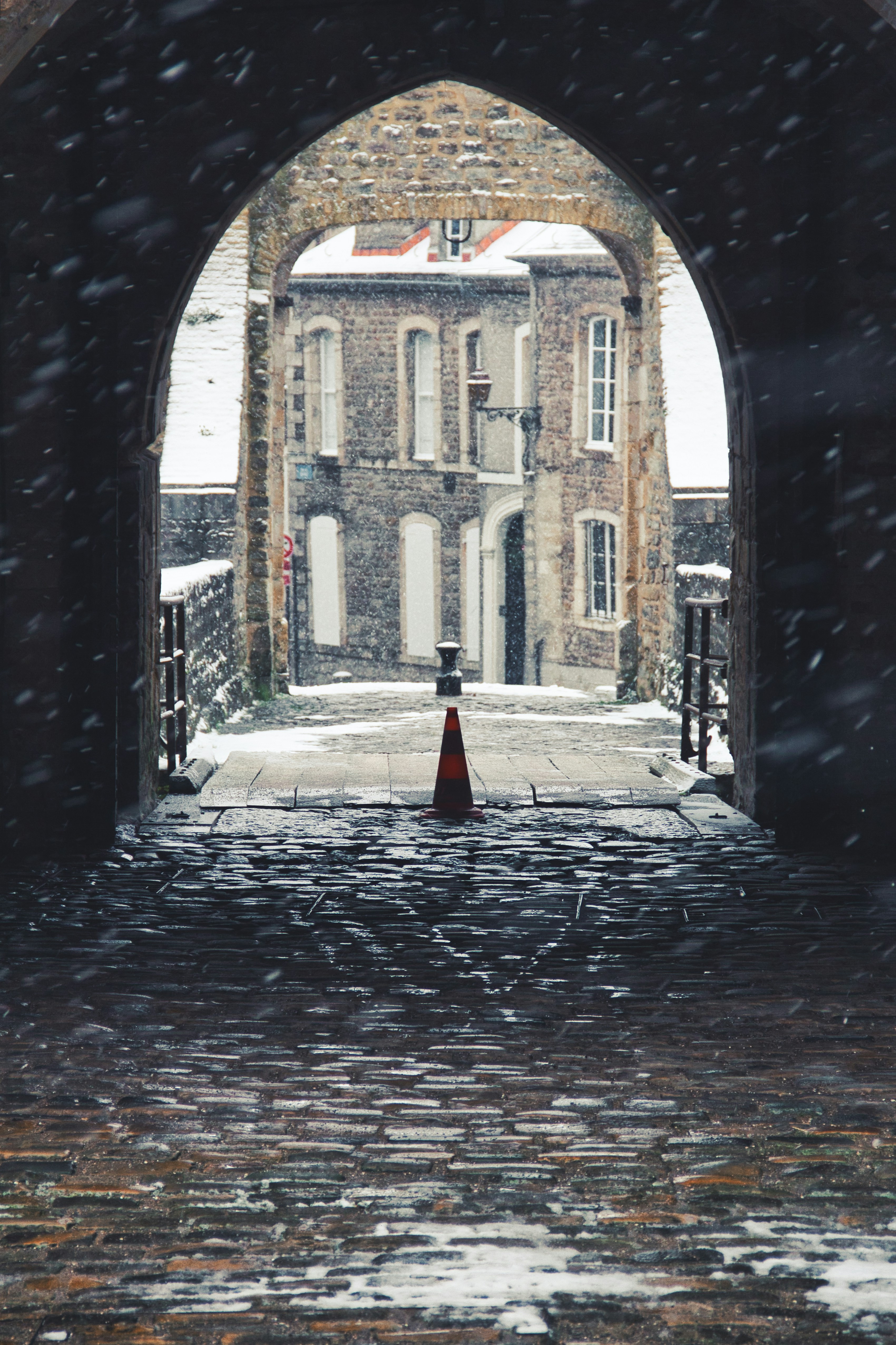 Snowfall at the Archway: The Red Cone at the Cobblestone Threshold