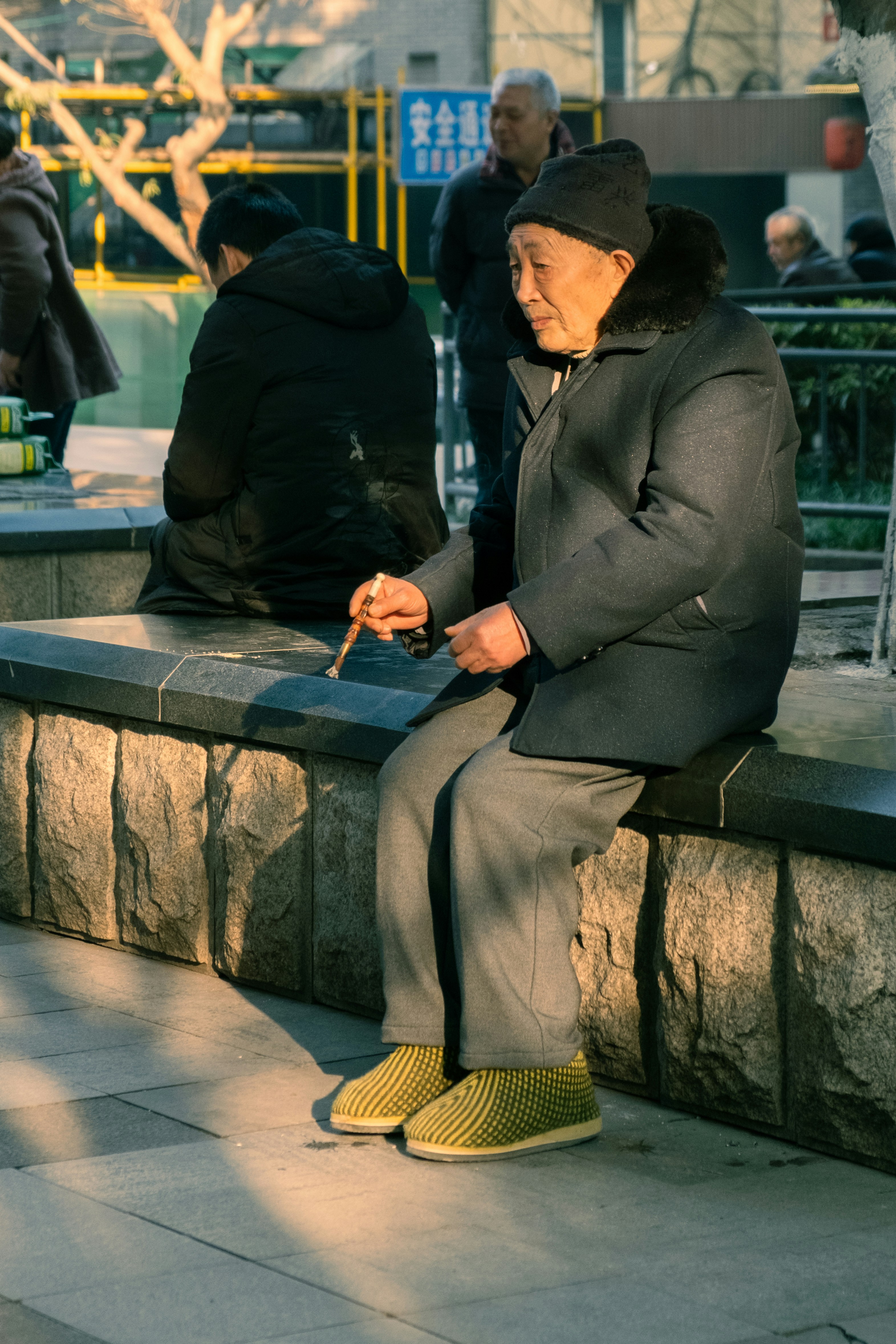 man in black suit jacket and gray pants sitting on gray concrete bench during daytime