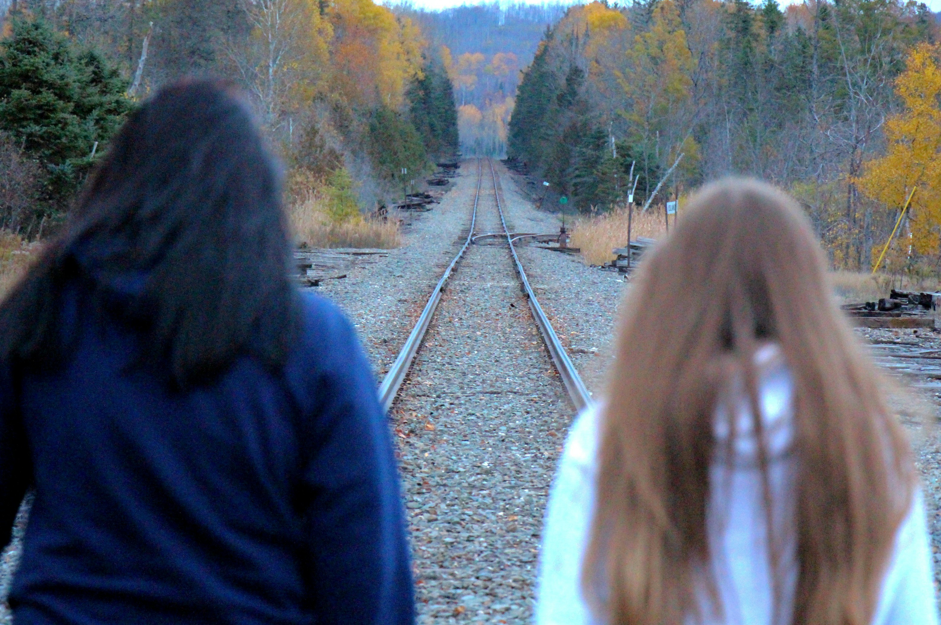 2 women walking on train rail during daytime photo – Free Grey Image on ...