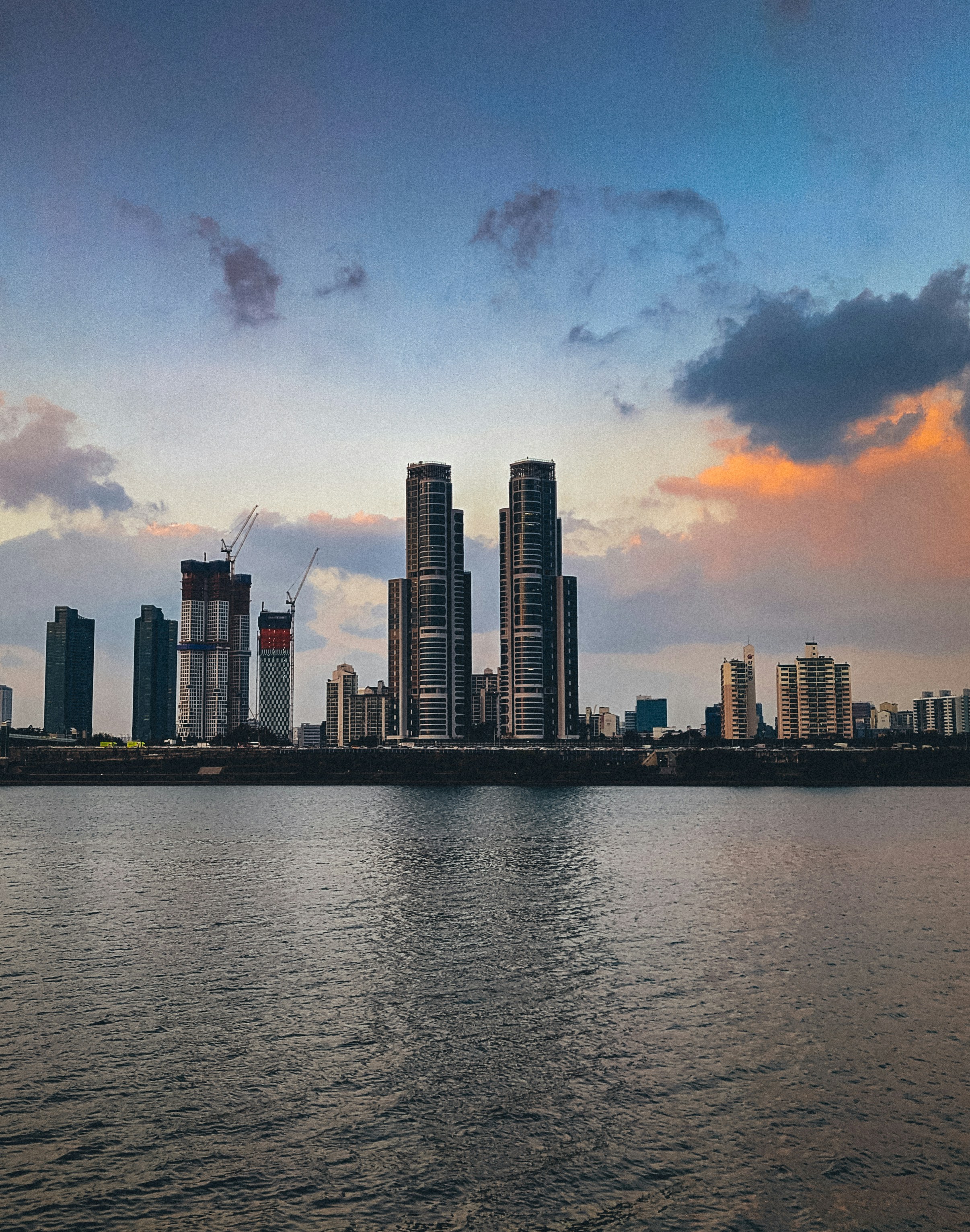 Horizonte de la ciudad a través del cuerpo de agua durante la puesta ...
