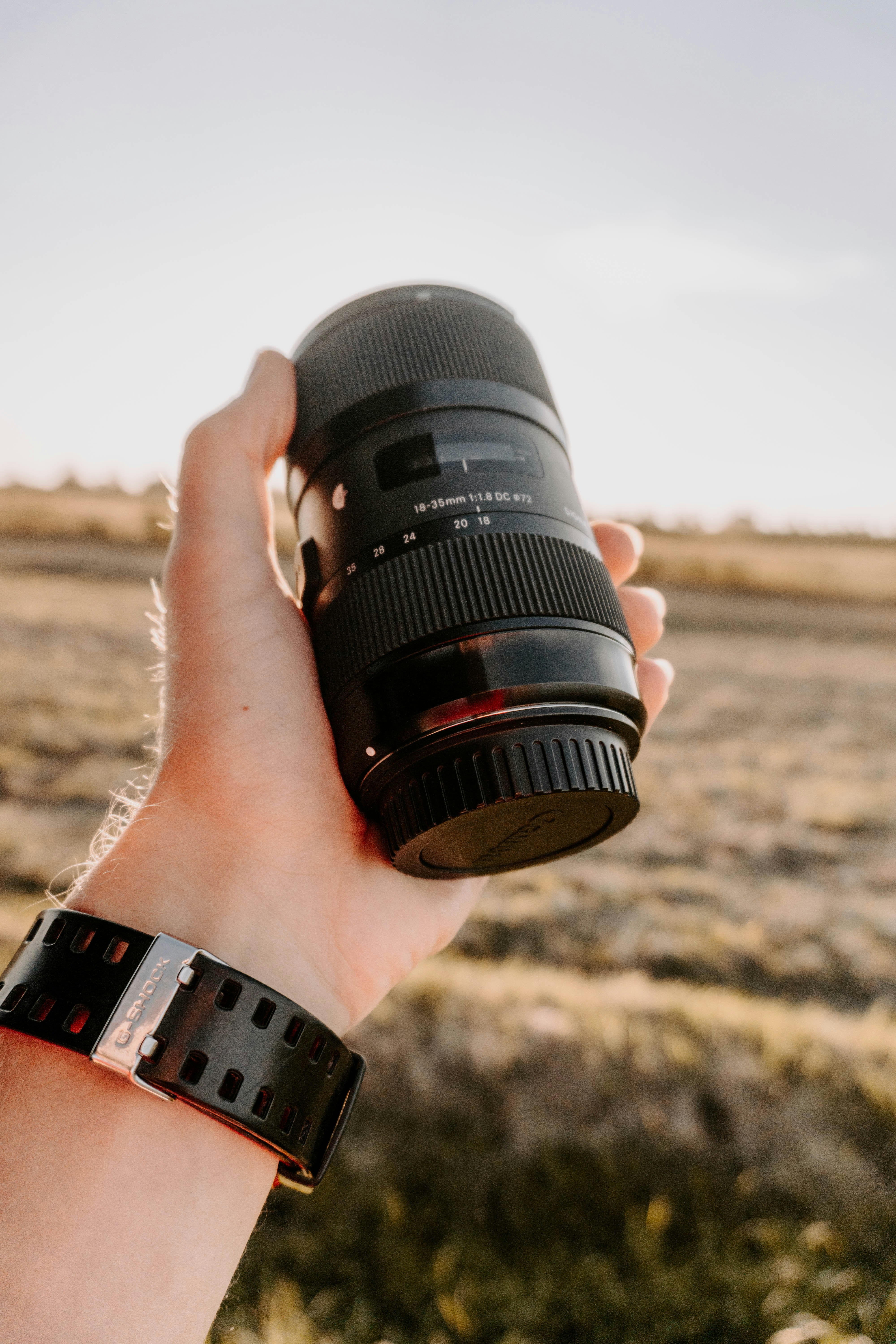 Golden Hour Grip: Clasping an 18-55mm Kit Lens in a Sunlit Field