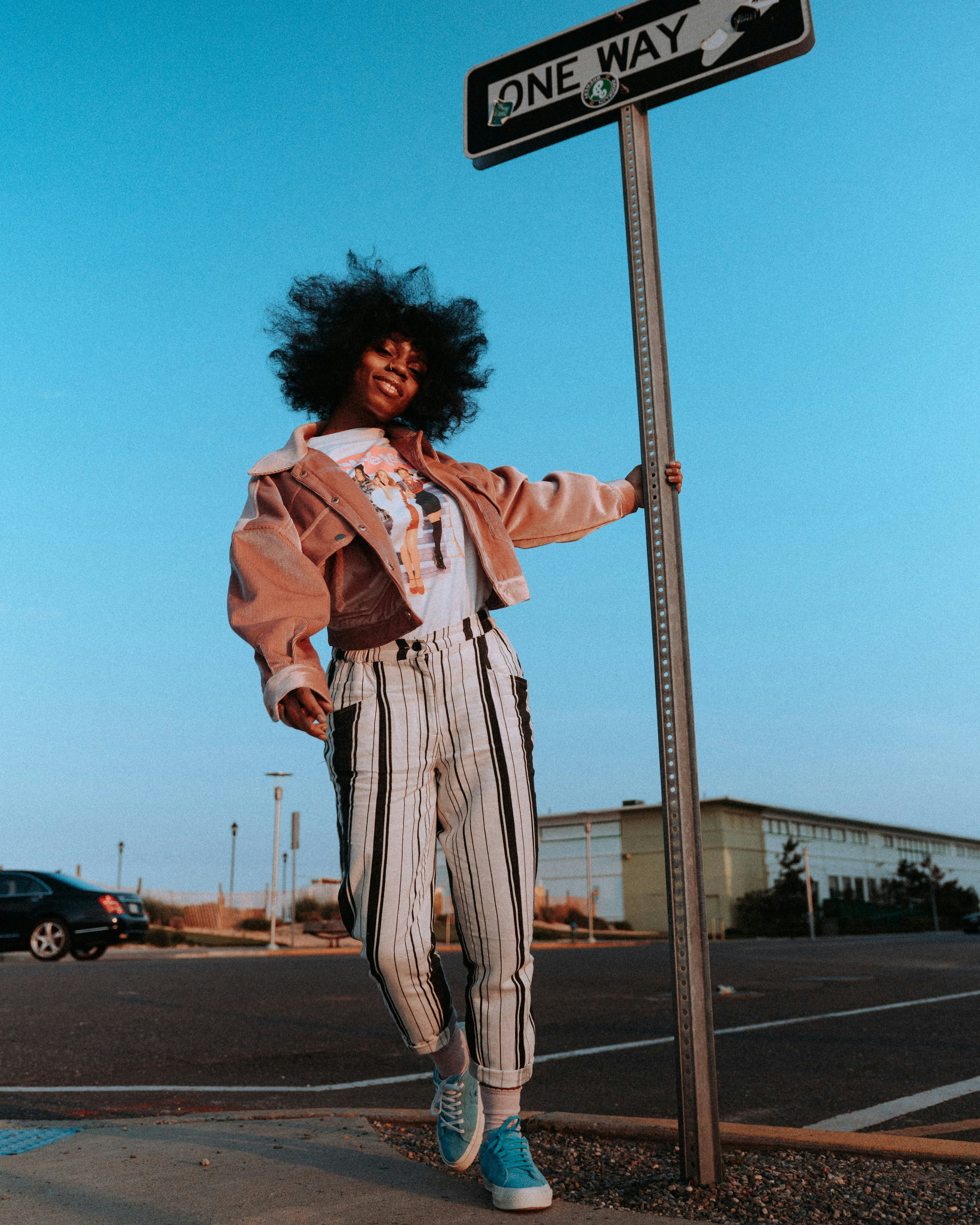 Bold stride under a blue sky: a street-style portrait by the sign