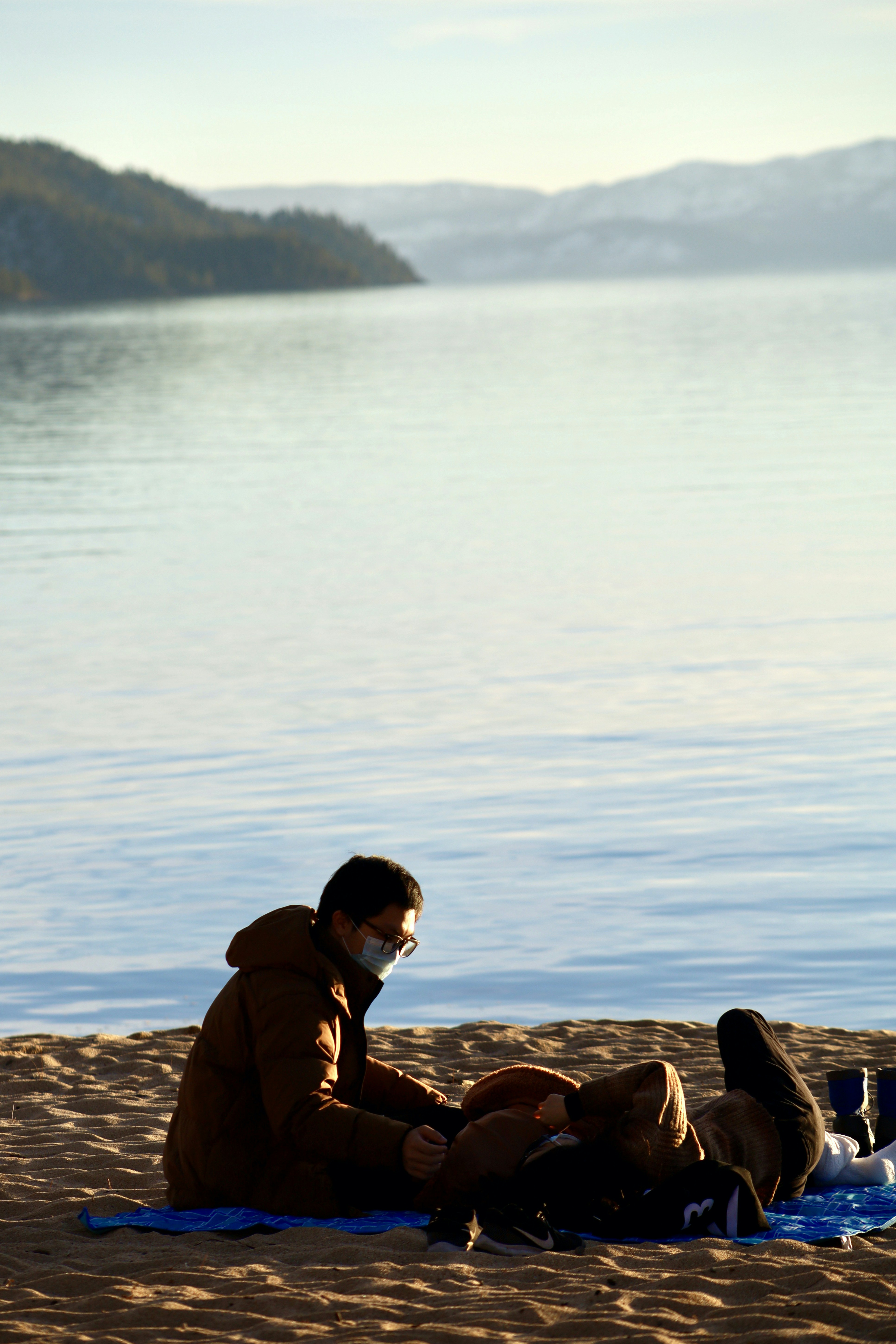Masked Moment by the Lakeside: A Quiet Pause on Sand