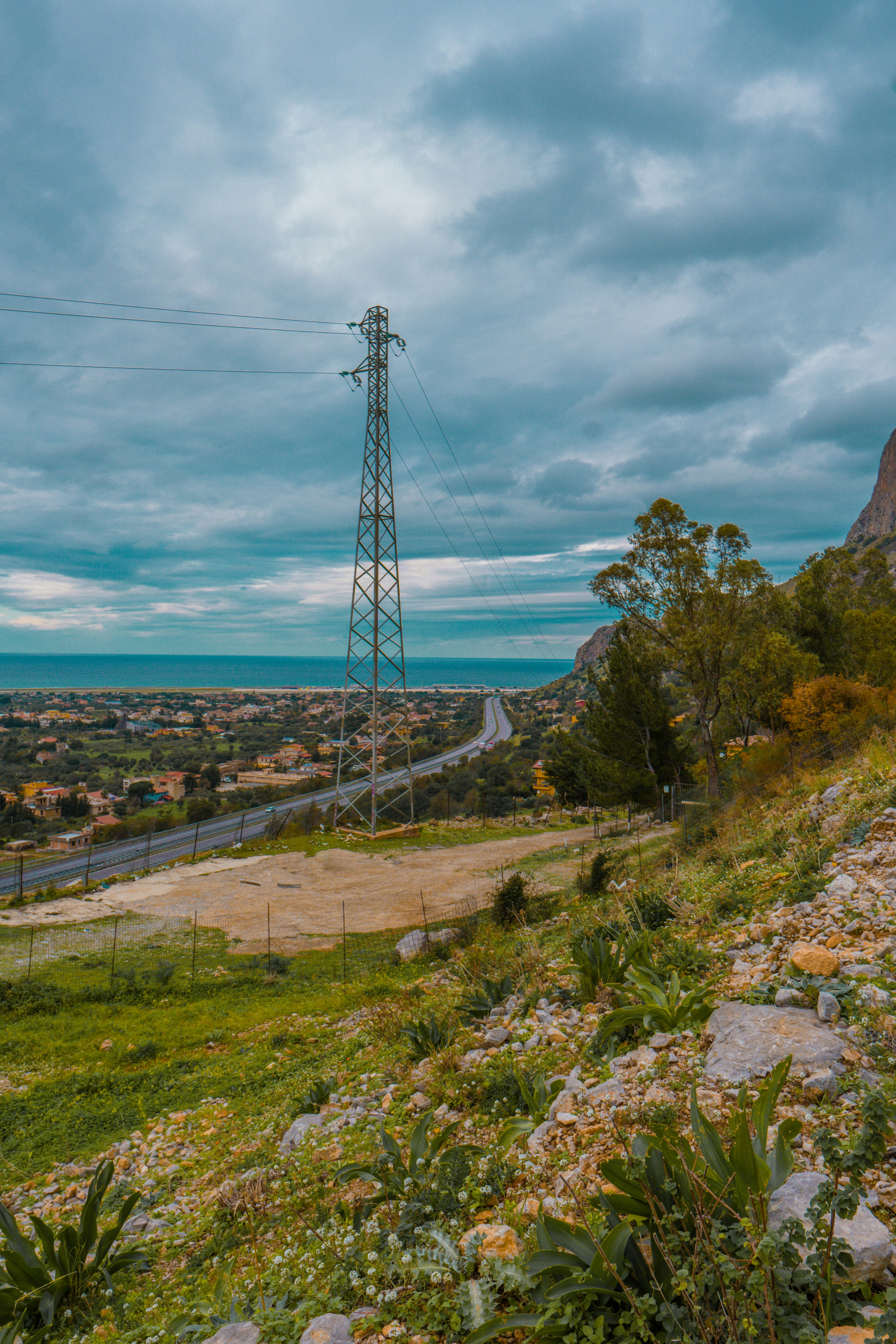 Lattice Tower Framing a Winding Hill Road Toward the Sea