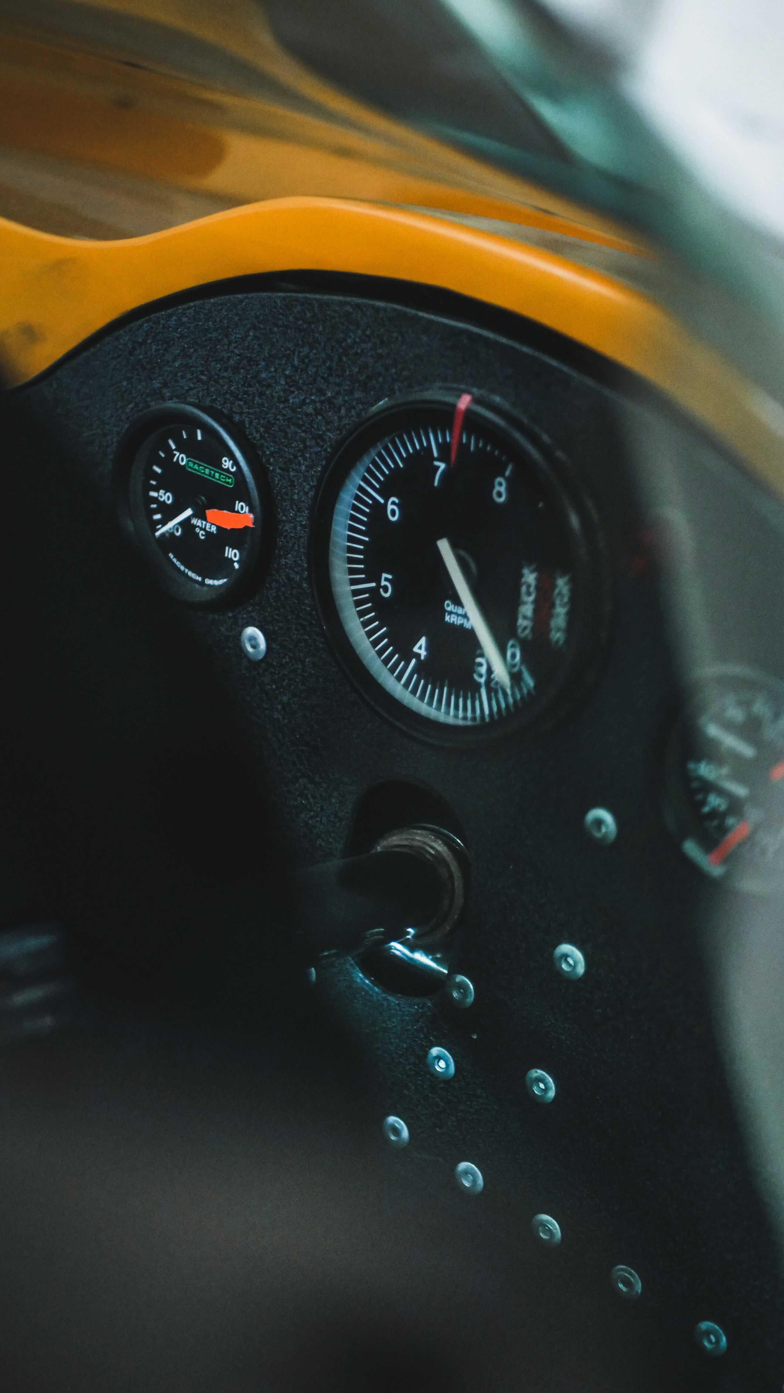 Close-up of a racing dashboard showcasing gauges and controls in a vibrant yellow setting.