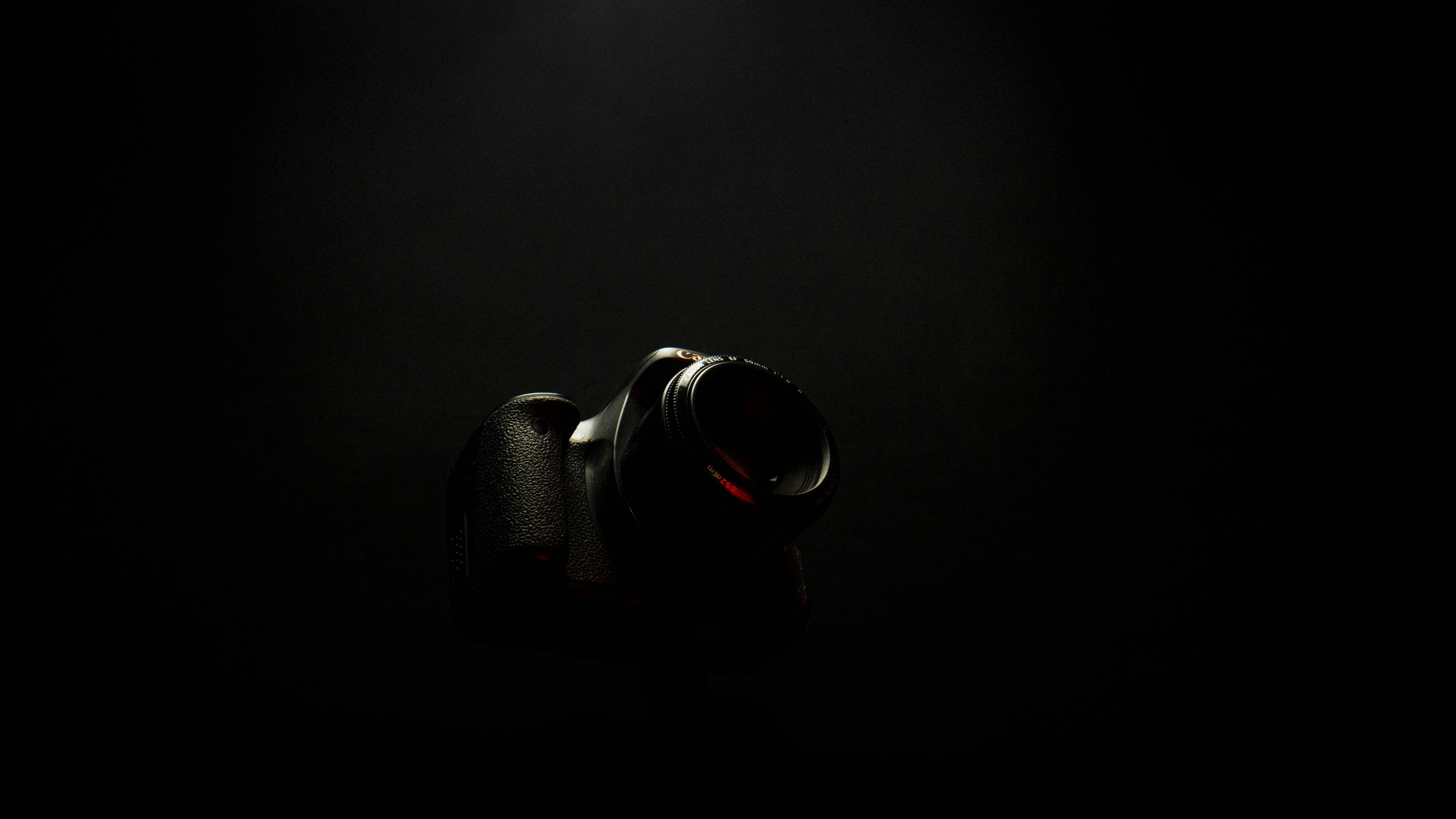Black DSLR camera subtly illuminated against a dark background.