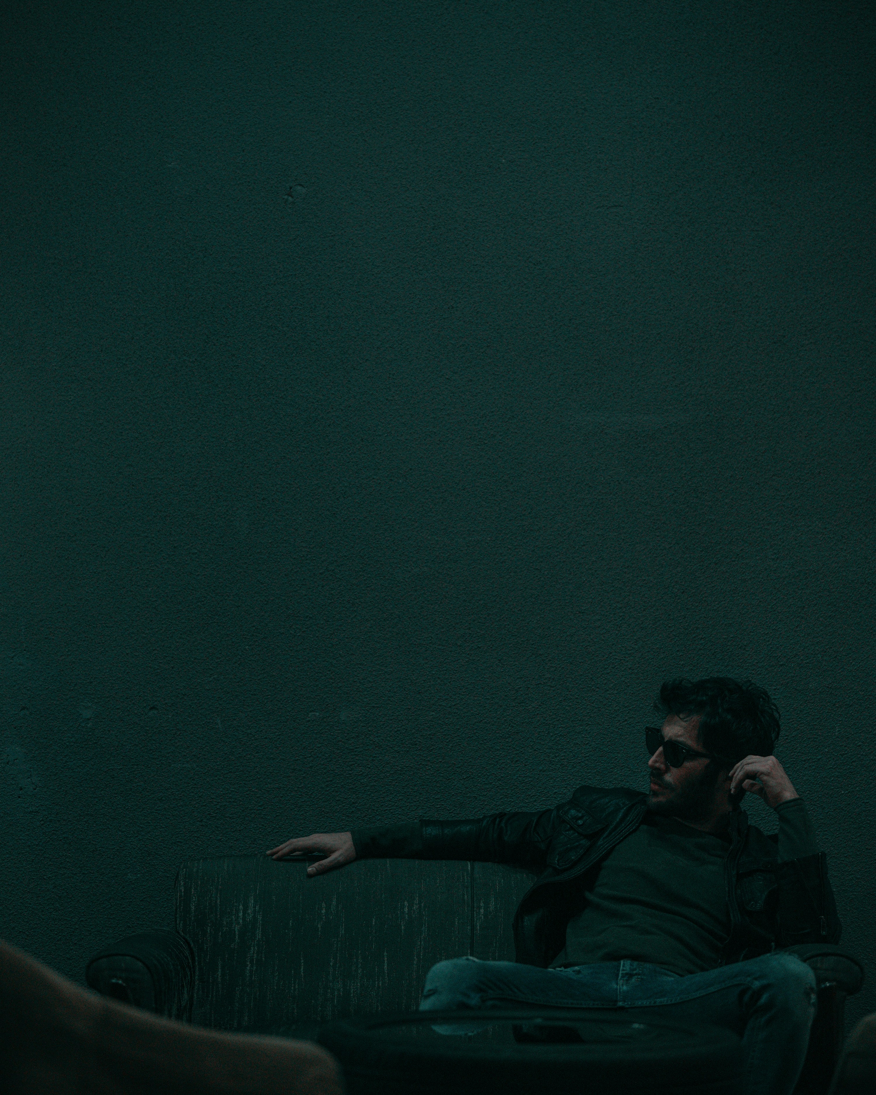 man in green jacket sitting on couch