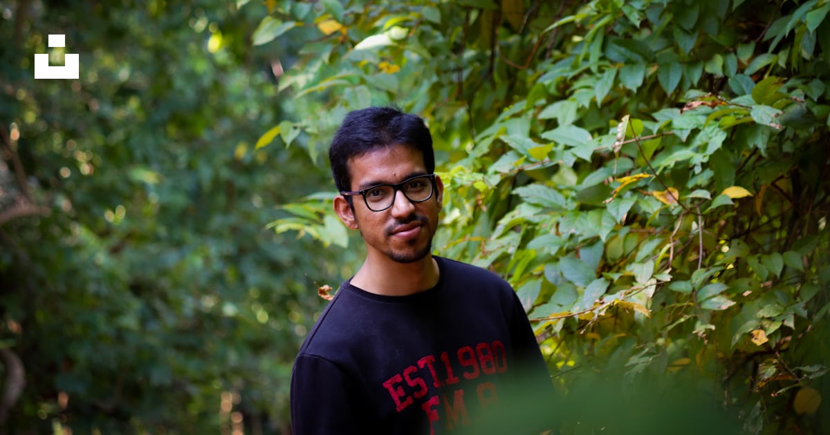 Man In Black Crew Neck Shirt Standing Beside Green Leaves During