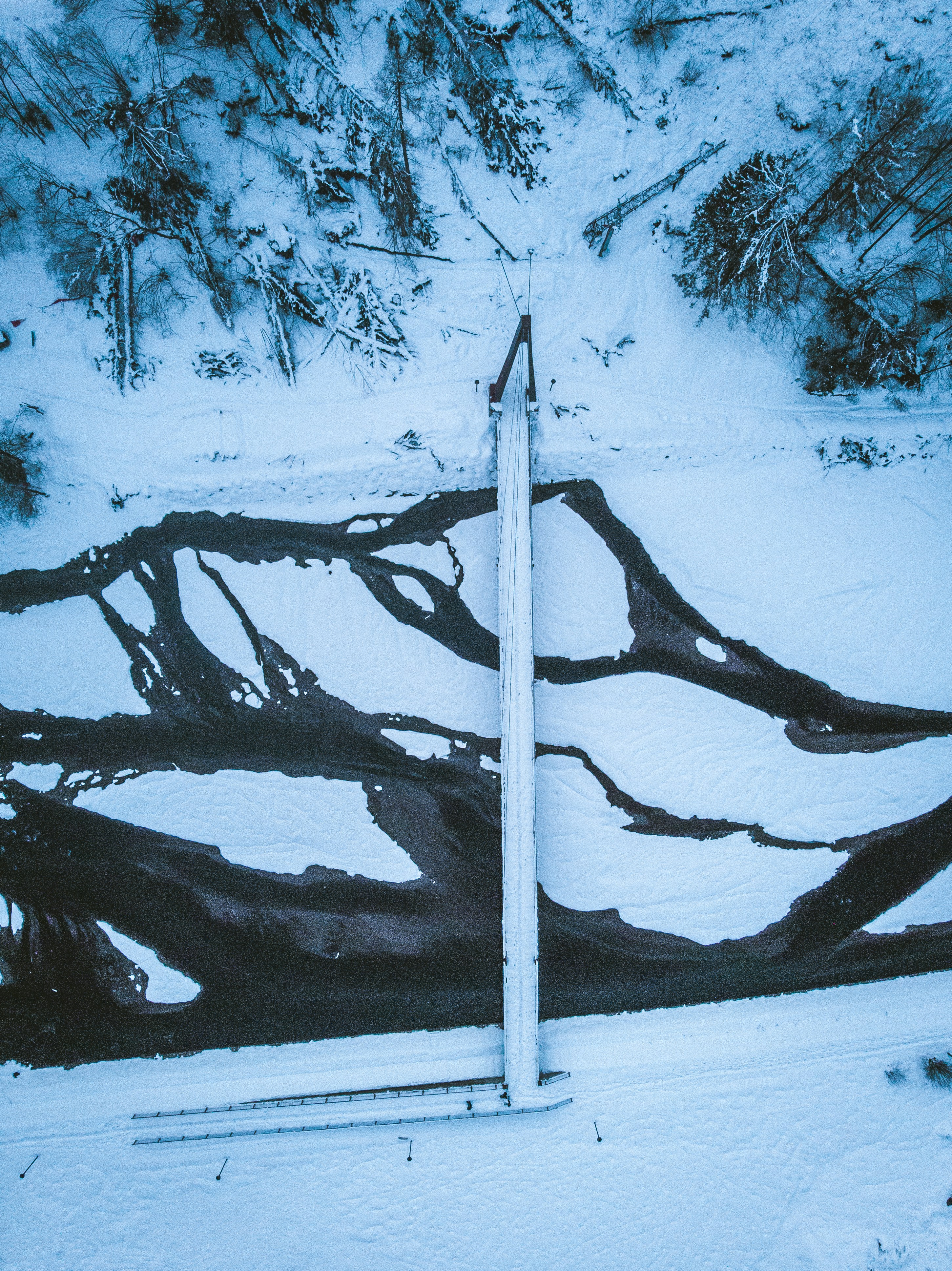 Vertical Spine Over Snowbound River: Aerial Perspective of a Bridge Crossing Serpentine Waters