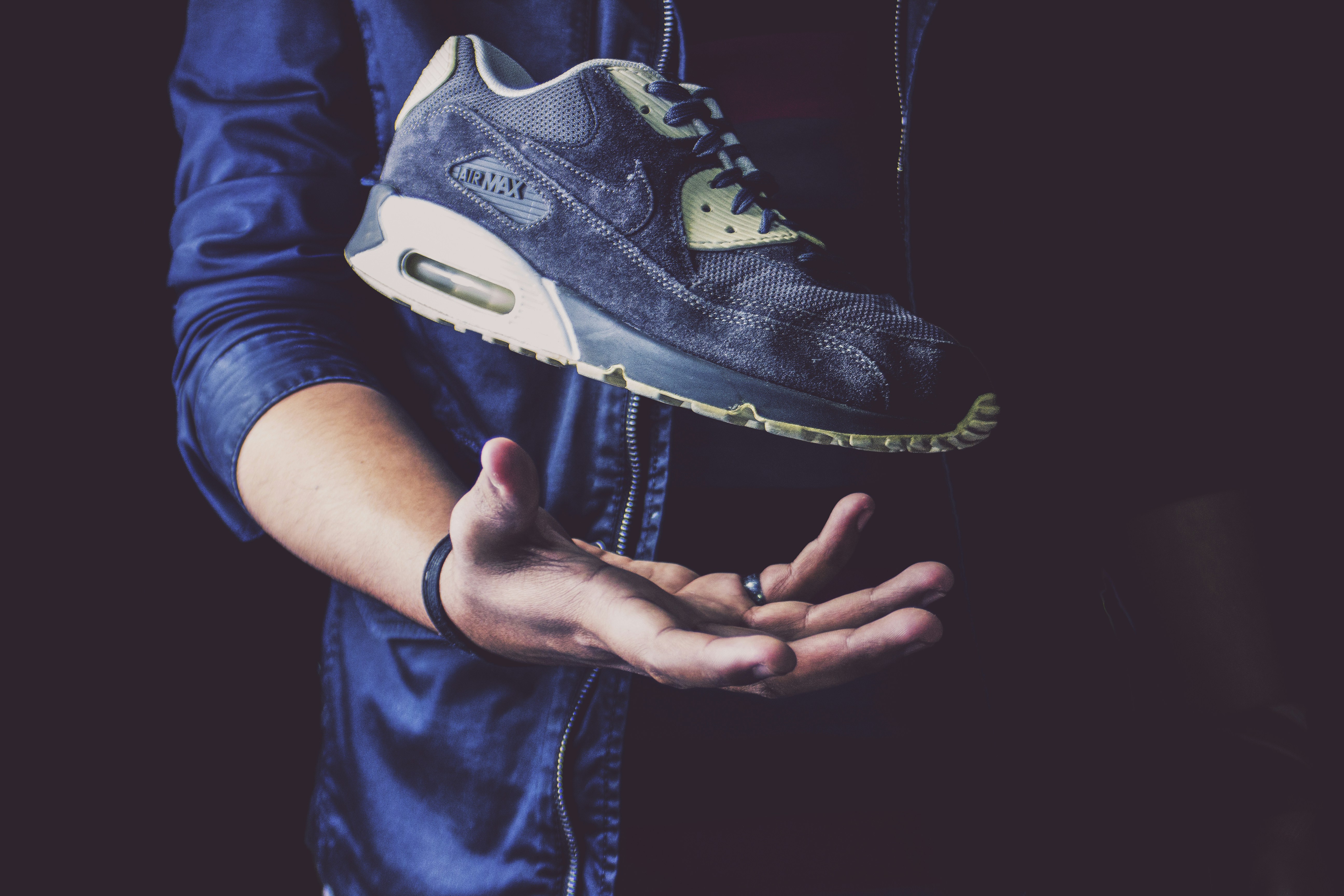 Floating sneaker above an outstretched hand against a dark background.