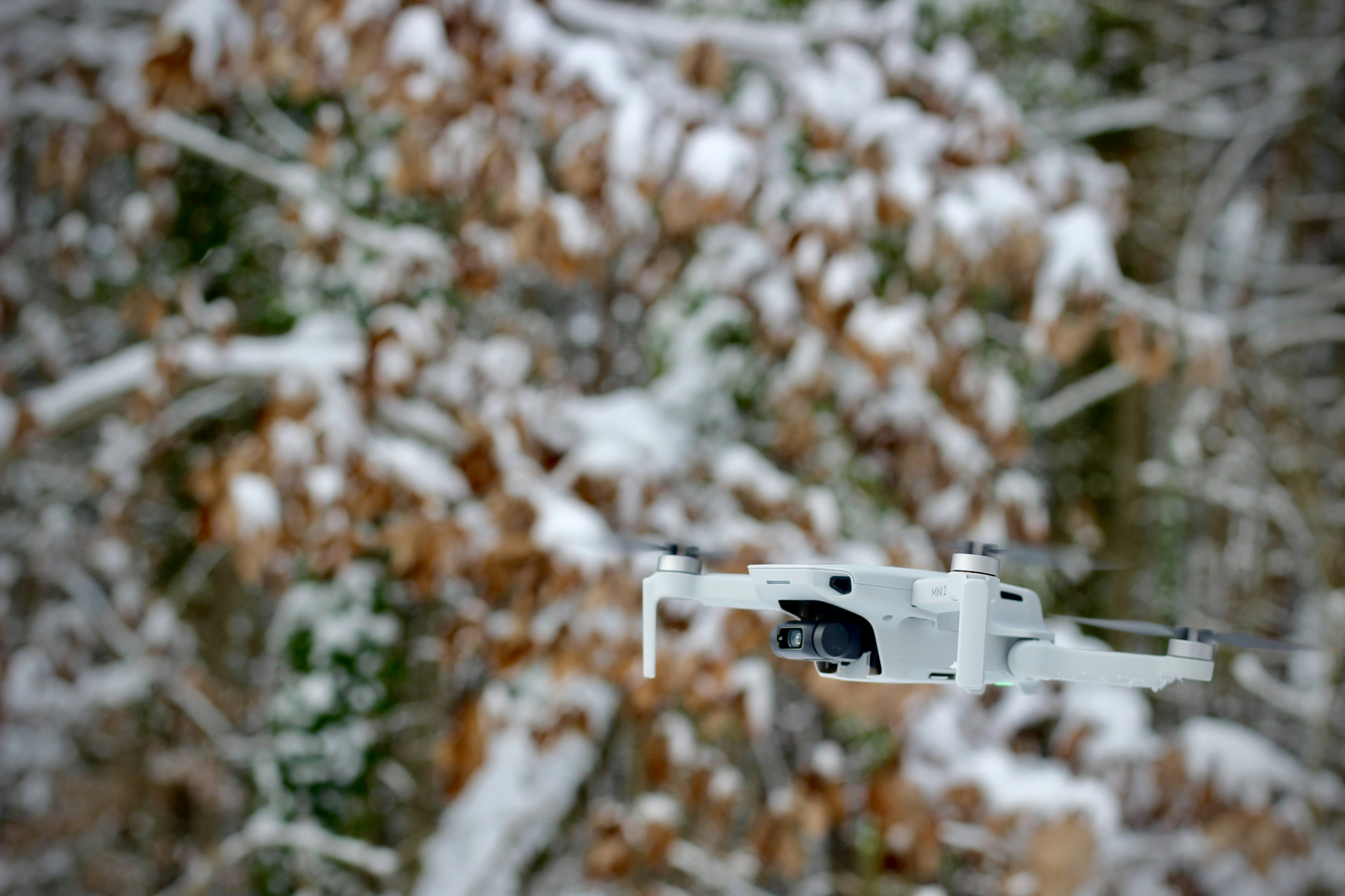 white drone flying over the trees