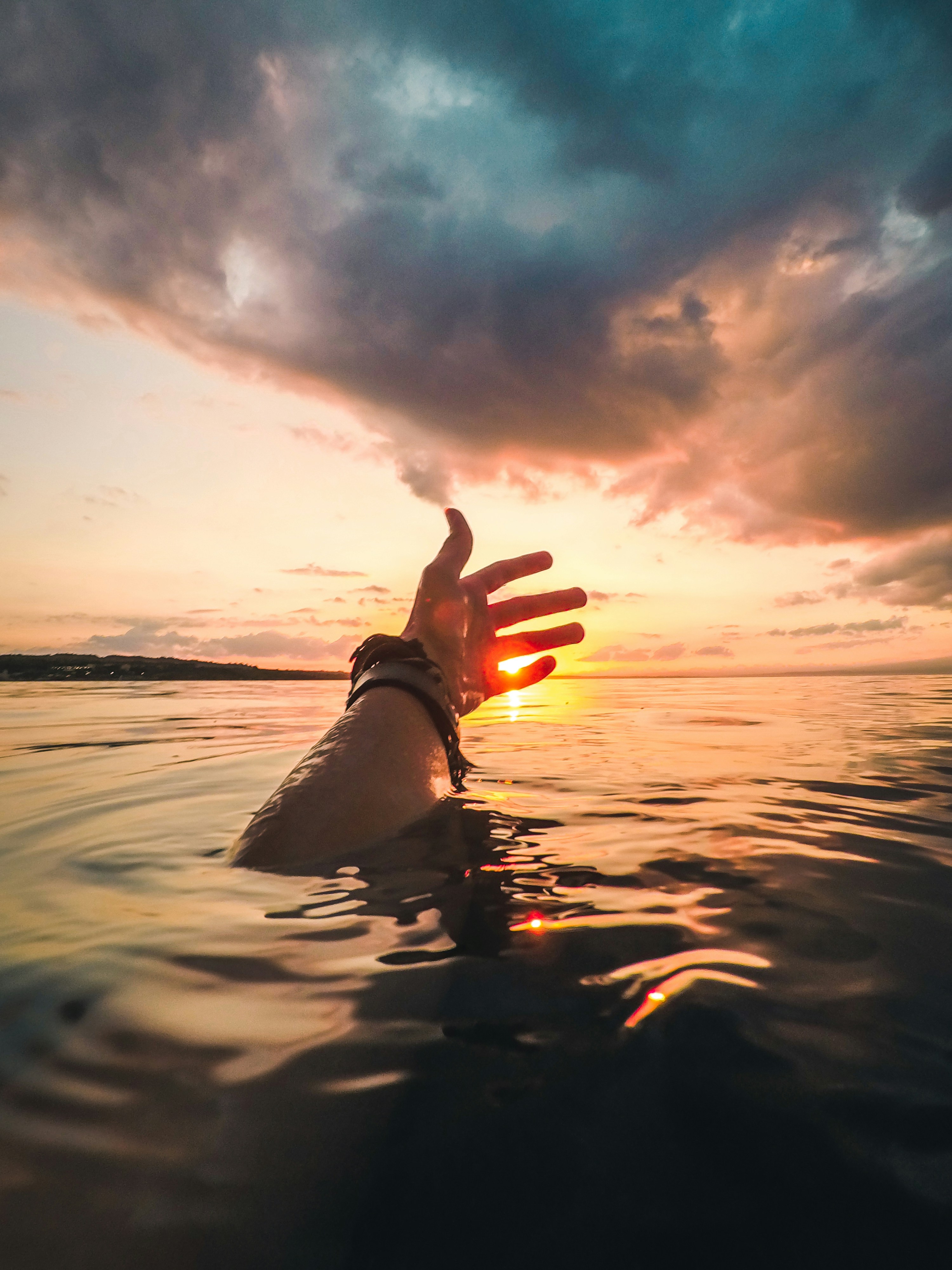 Outstretched Palm at Sunset: Golden Ripples on a Quiet Sea