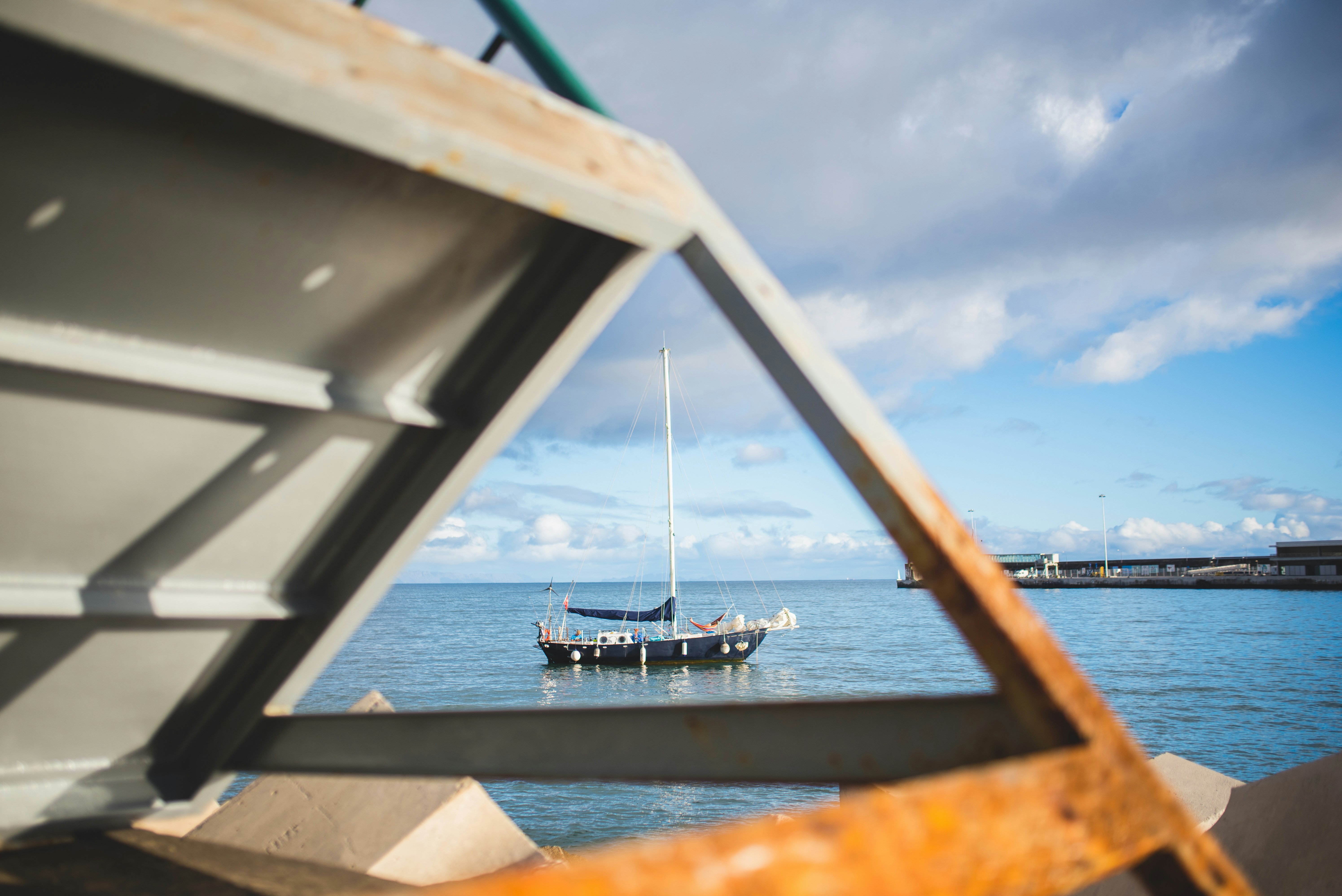 Framed Rust and Blue Harbor: a lone sailboat on calm water