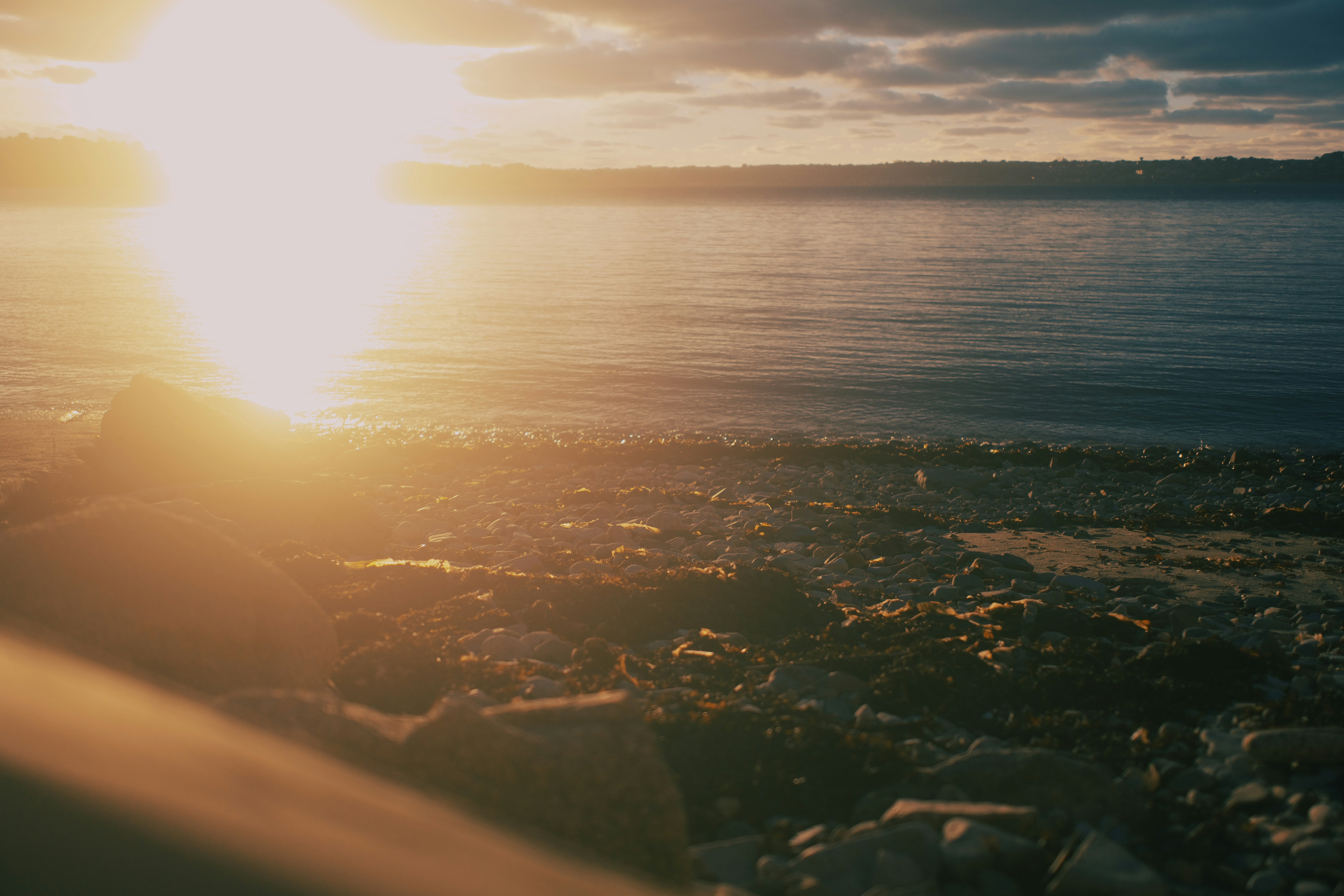 Sunflare over a Pebble Shore at Golden Hour