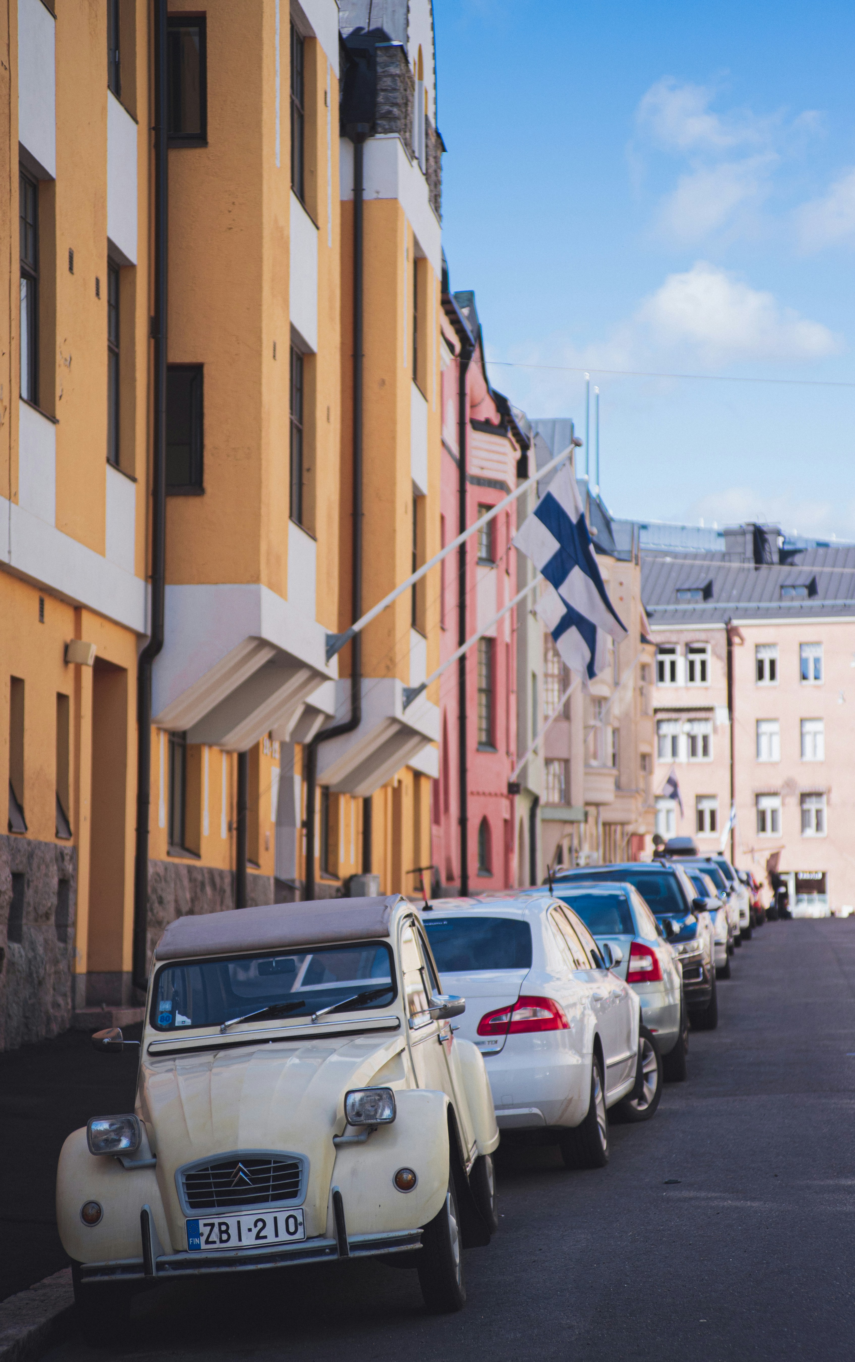 Cream Vintage Car Anchors a Sunlit Nordic Street with Pastel Facades
