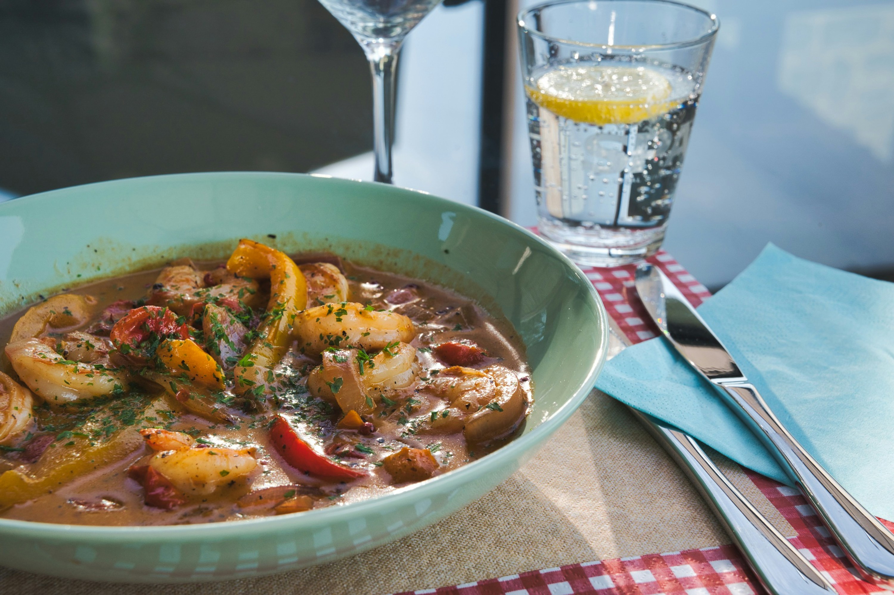 Sunlit bowl of hearty seafood stew on a checkered table