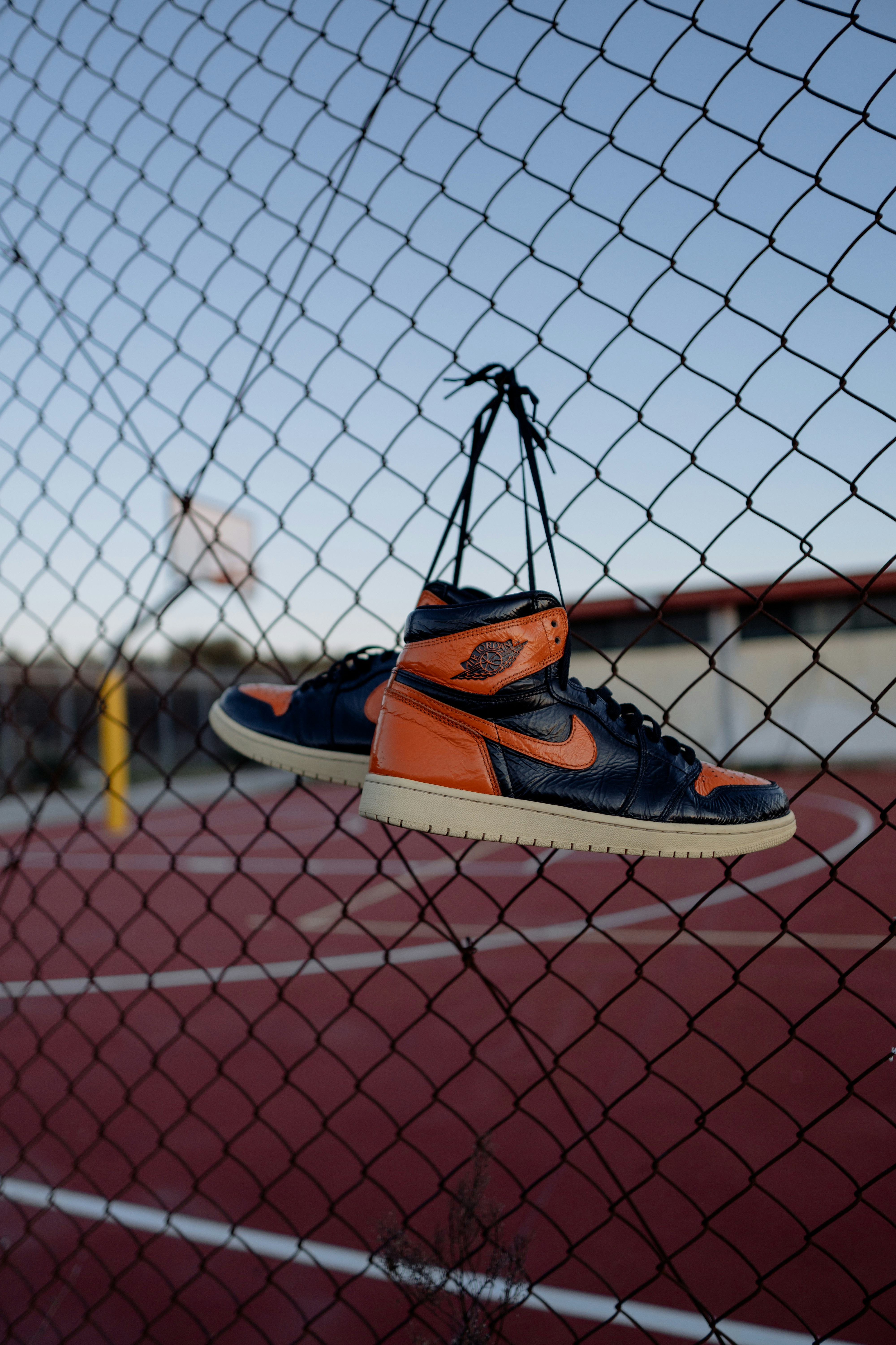 Orange and black nike athletic shoes on chain link fence photo – Free ...