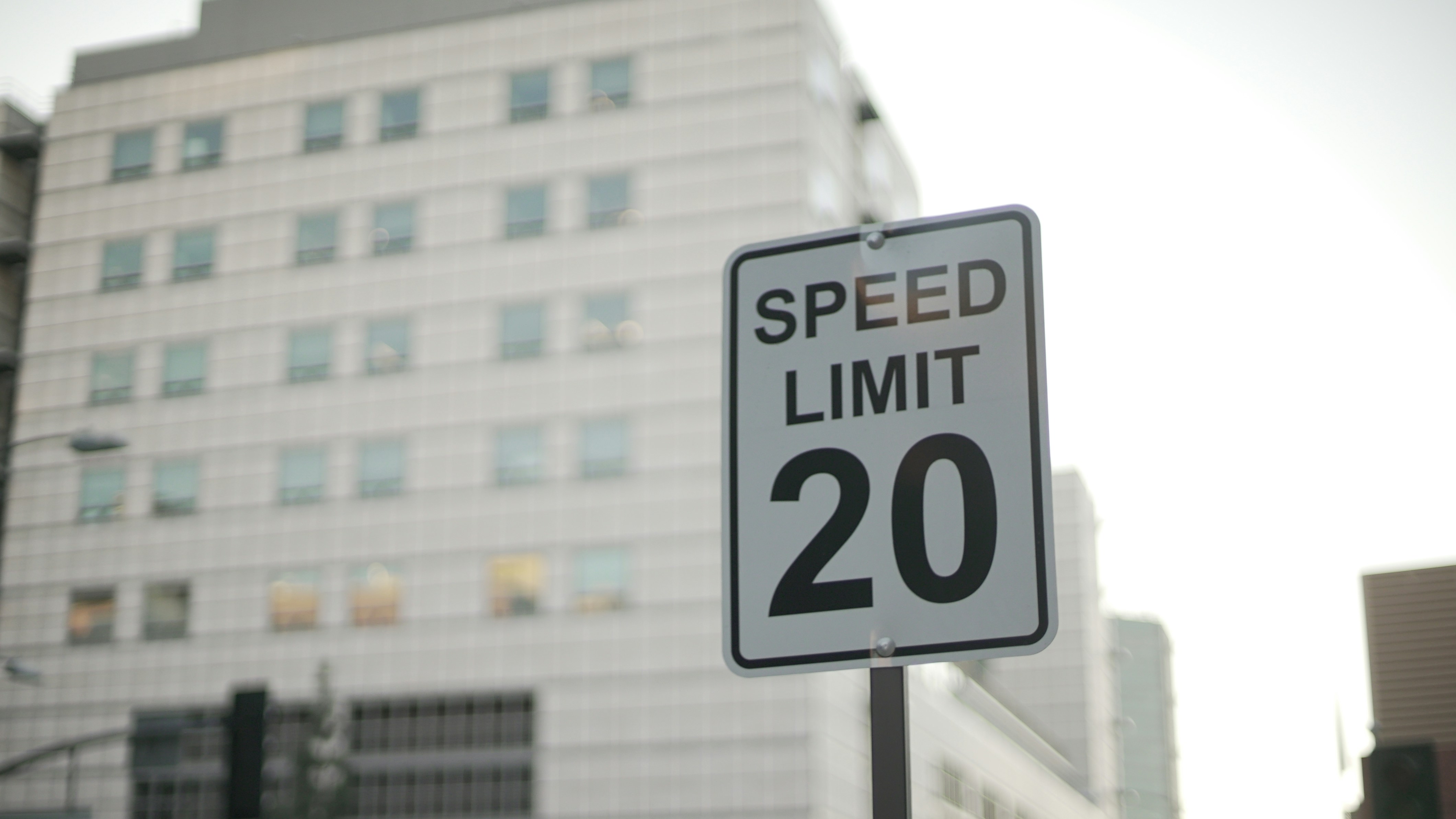 Speed Limit 20 Sign Anchors a Sunlit City Facade