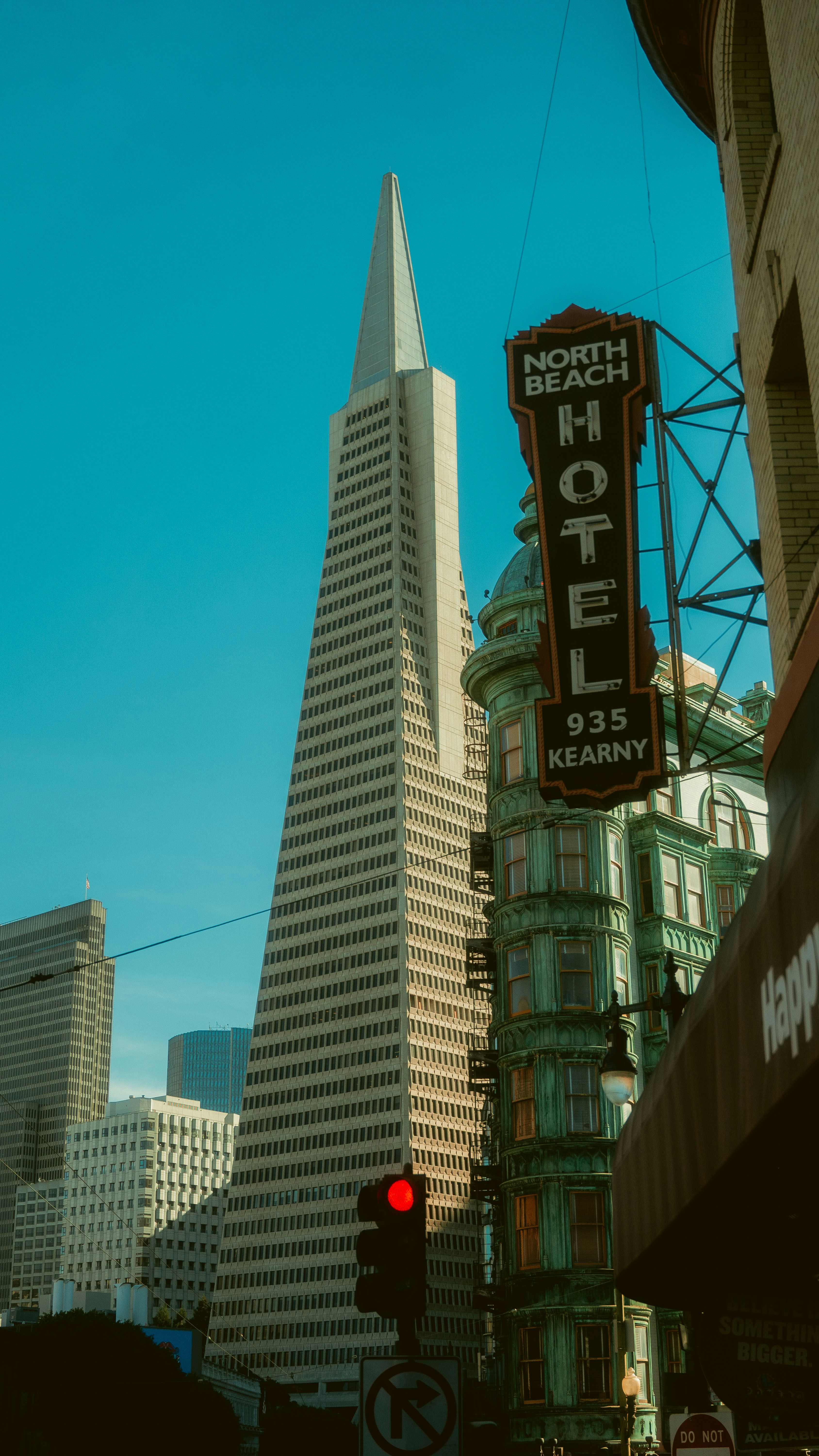 Neon Sign and Needle: San Francisco’s Hotel Spire Under a Clear Blue Sky
