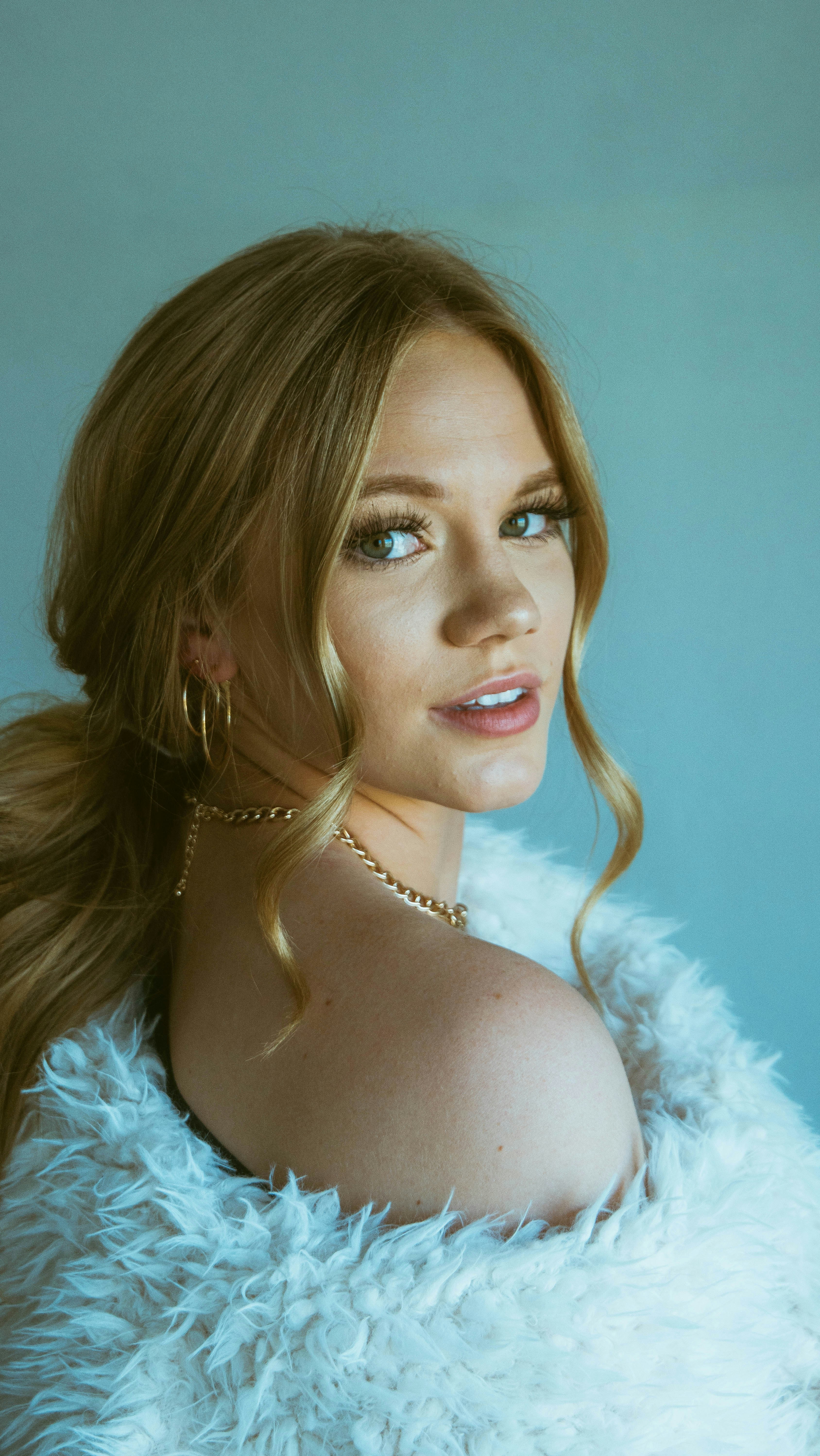Turquoise Glow: Portrait of a Golden-Haired Muse in Feathered White