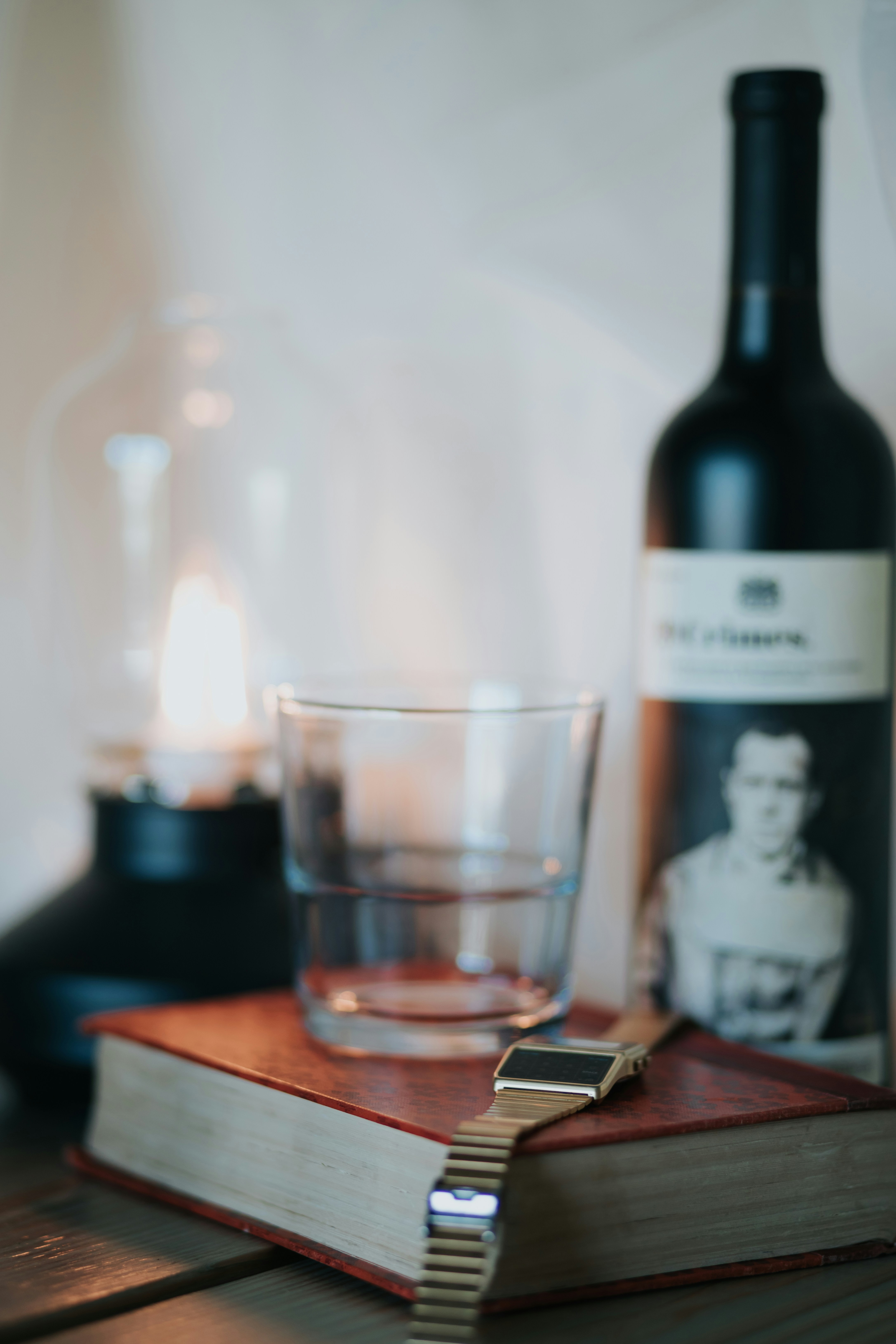 A Quiet Ritual: Glass, Book, and Bottle in Soft Lamplight