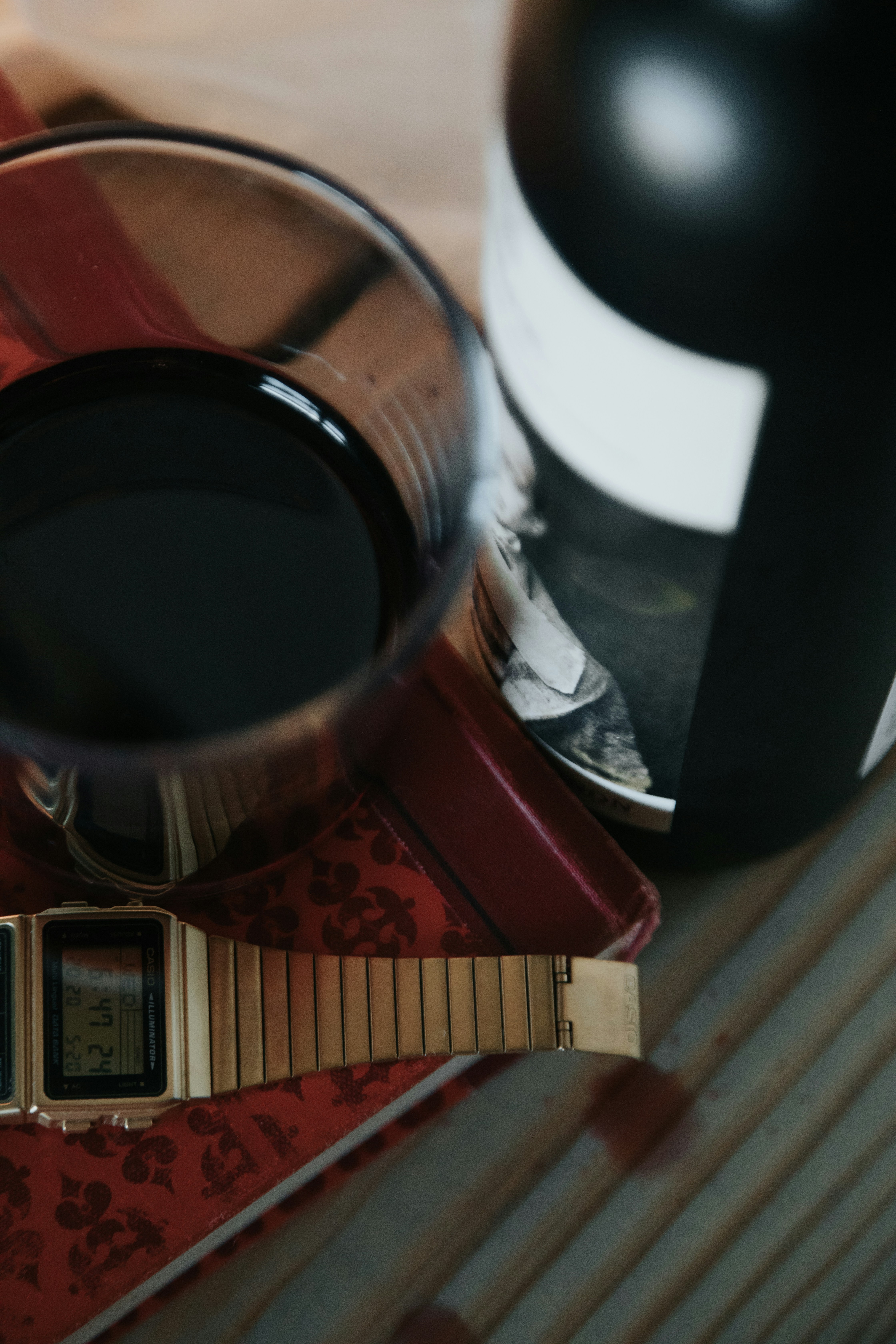 Gold Timekeeper, Dark Wine, and a Red-Patterned Page: A Quiet Desk Still Life