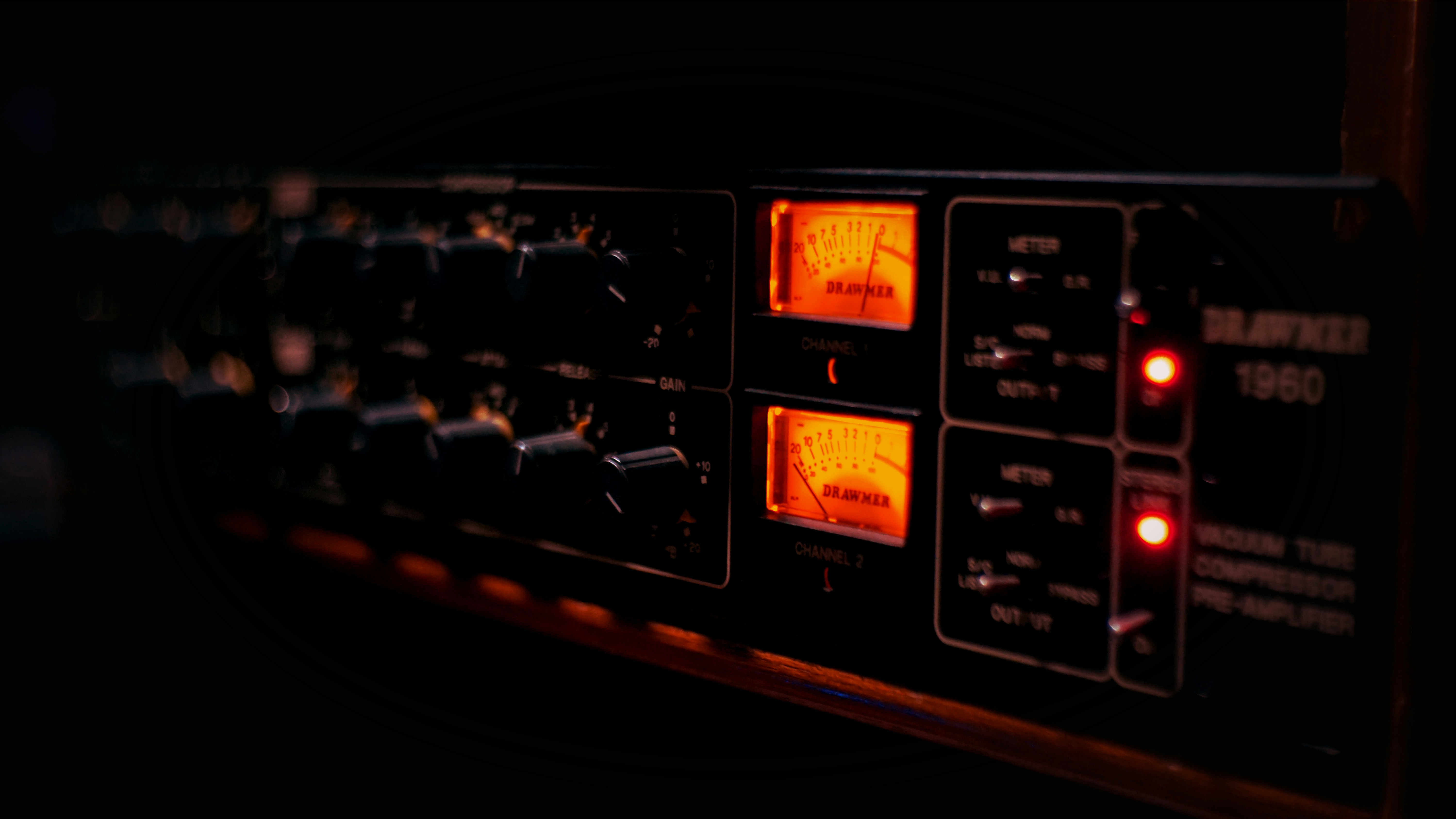 Vintage audio equipment with illuminated VU meters and control knobs, showcasing the intricate details of sound engineering technology.