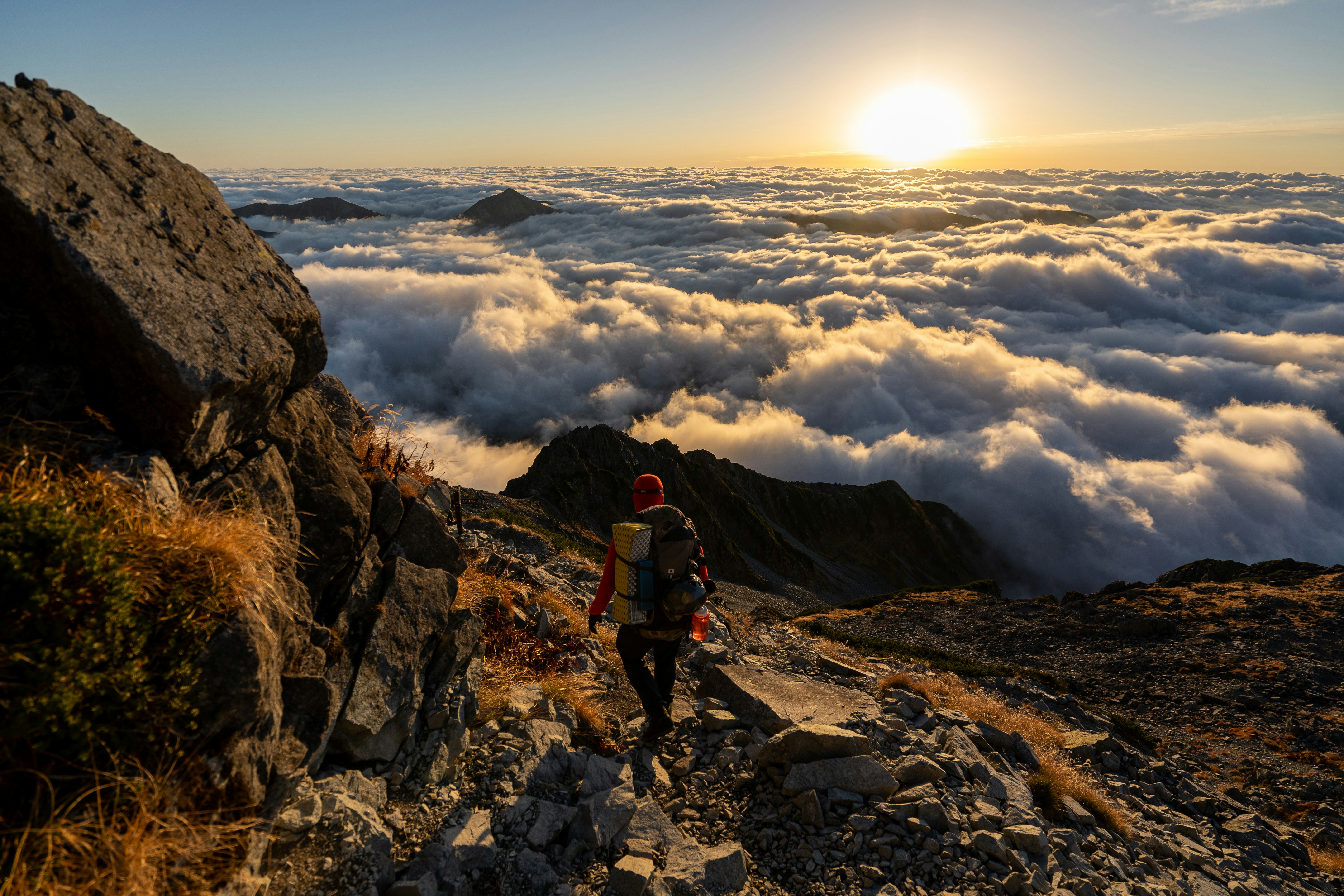 Early bird gets the worm. Northern alps in Japan.  | man in red jacket and black pants standing on rocky mountain during daytime