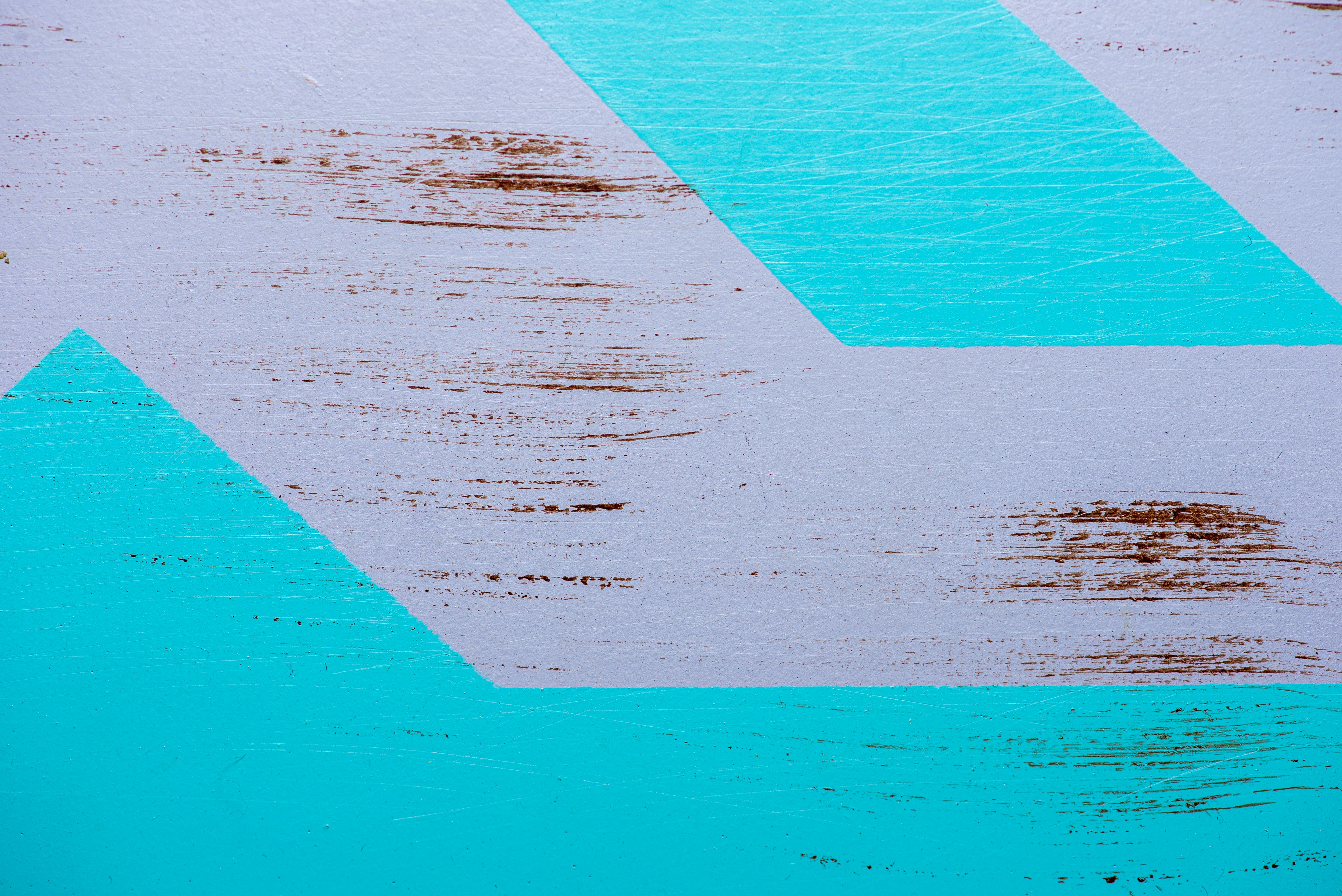 Abstract design featuring turquoise and gray chevron patterns with visible wear and texture.