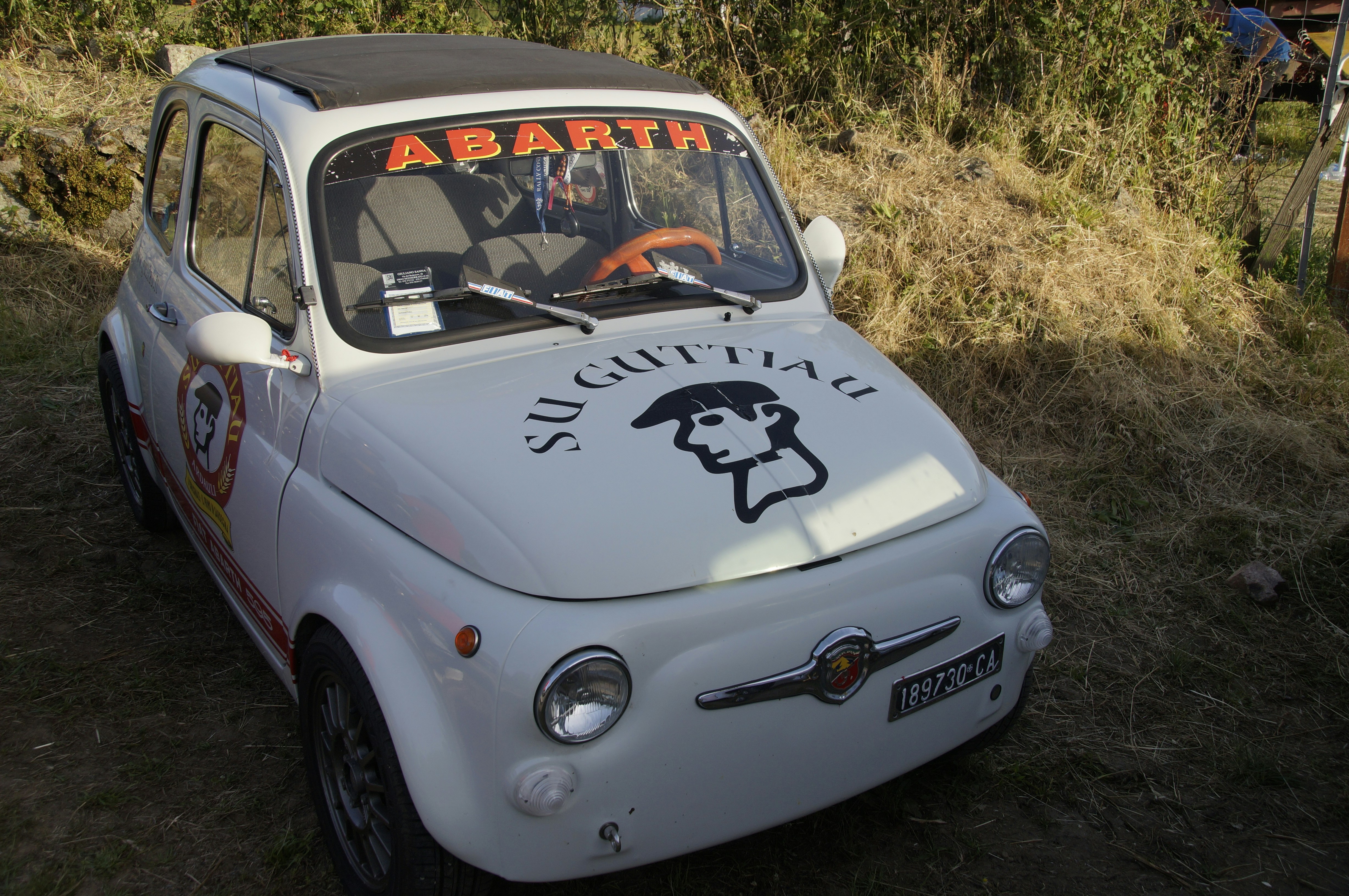 Dusty Rally Nostalgia: White Fiat 500 Abarth with Hood Art in a Dry Field
