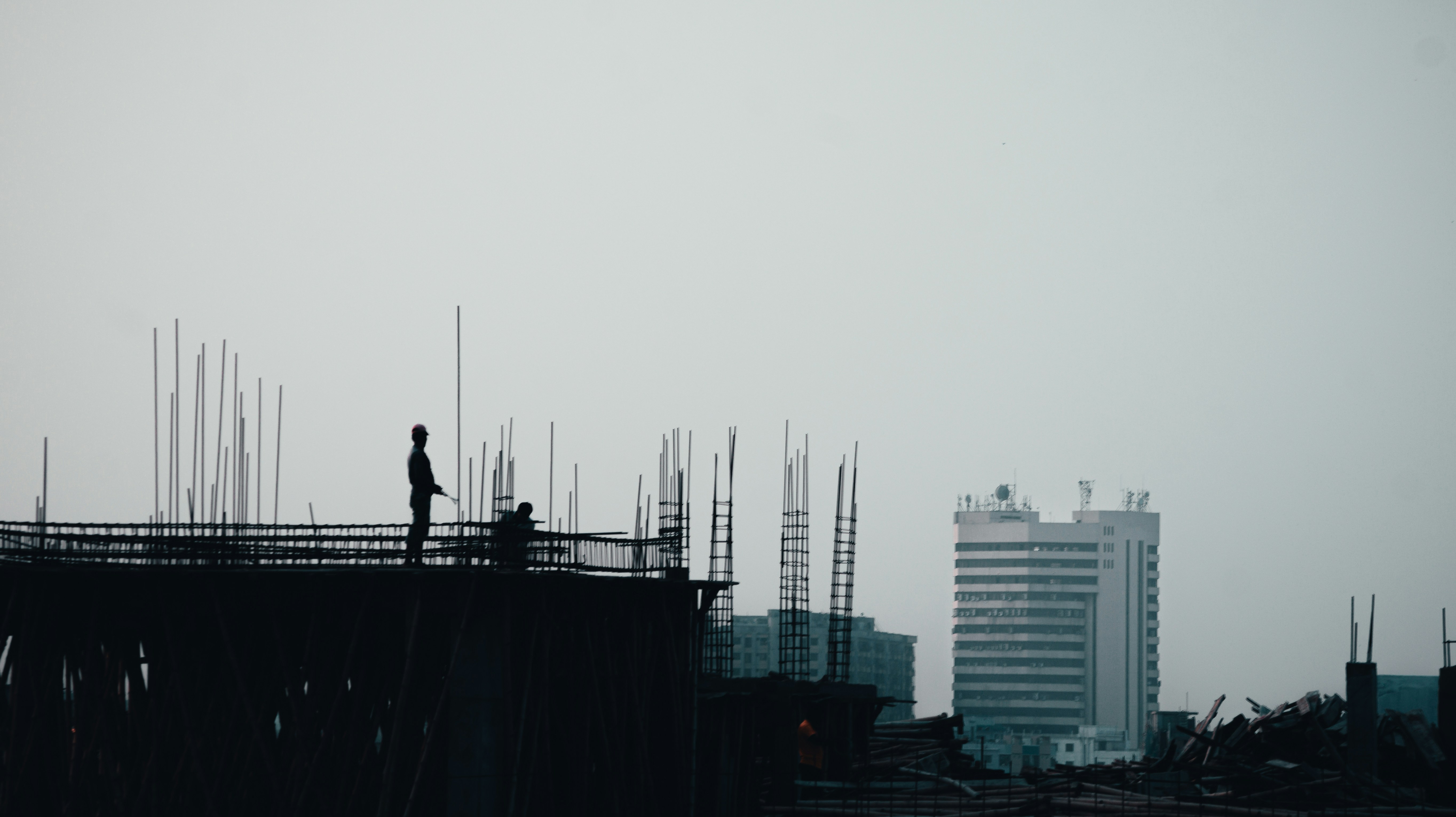 Edge of Ascent: silhouette on scaffolding against a hazy cityscape