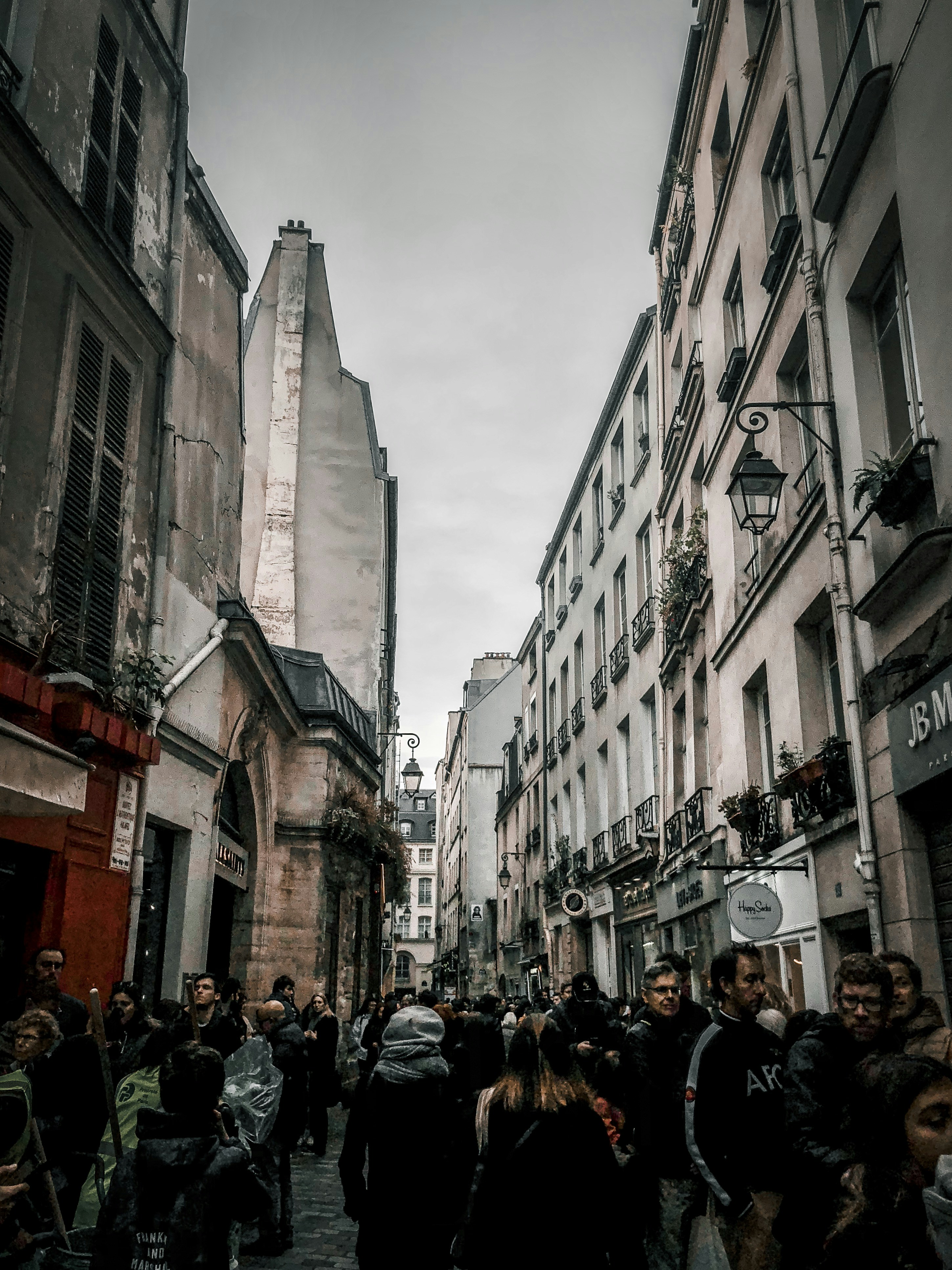 Bustling narrow street in Paris filled with pedestrians and charming architecture, capturing the essence of city life.