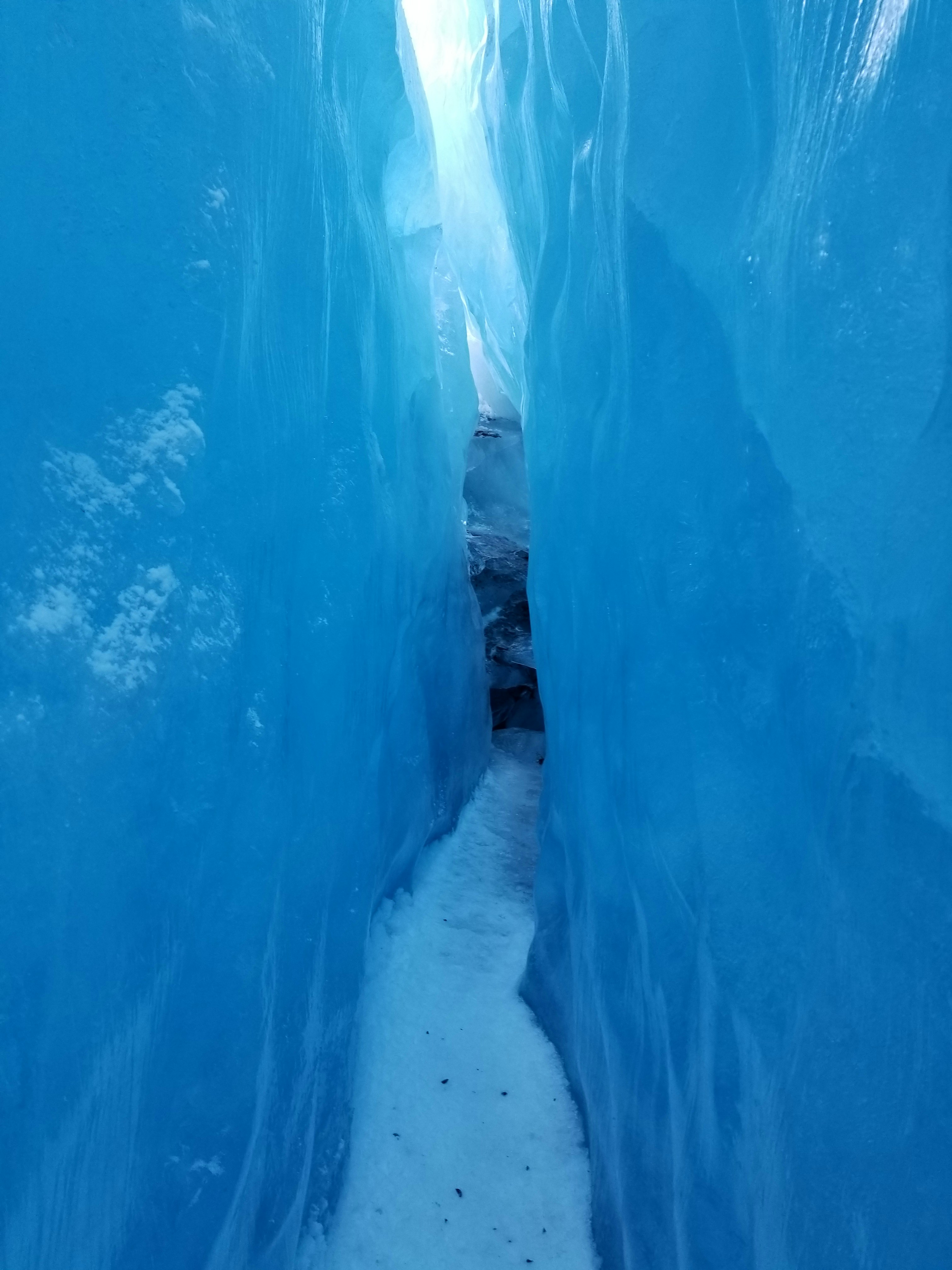 Blue Ice Chasm: A Narrow Glacial Corridor Toward a Distant Glow