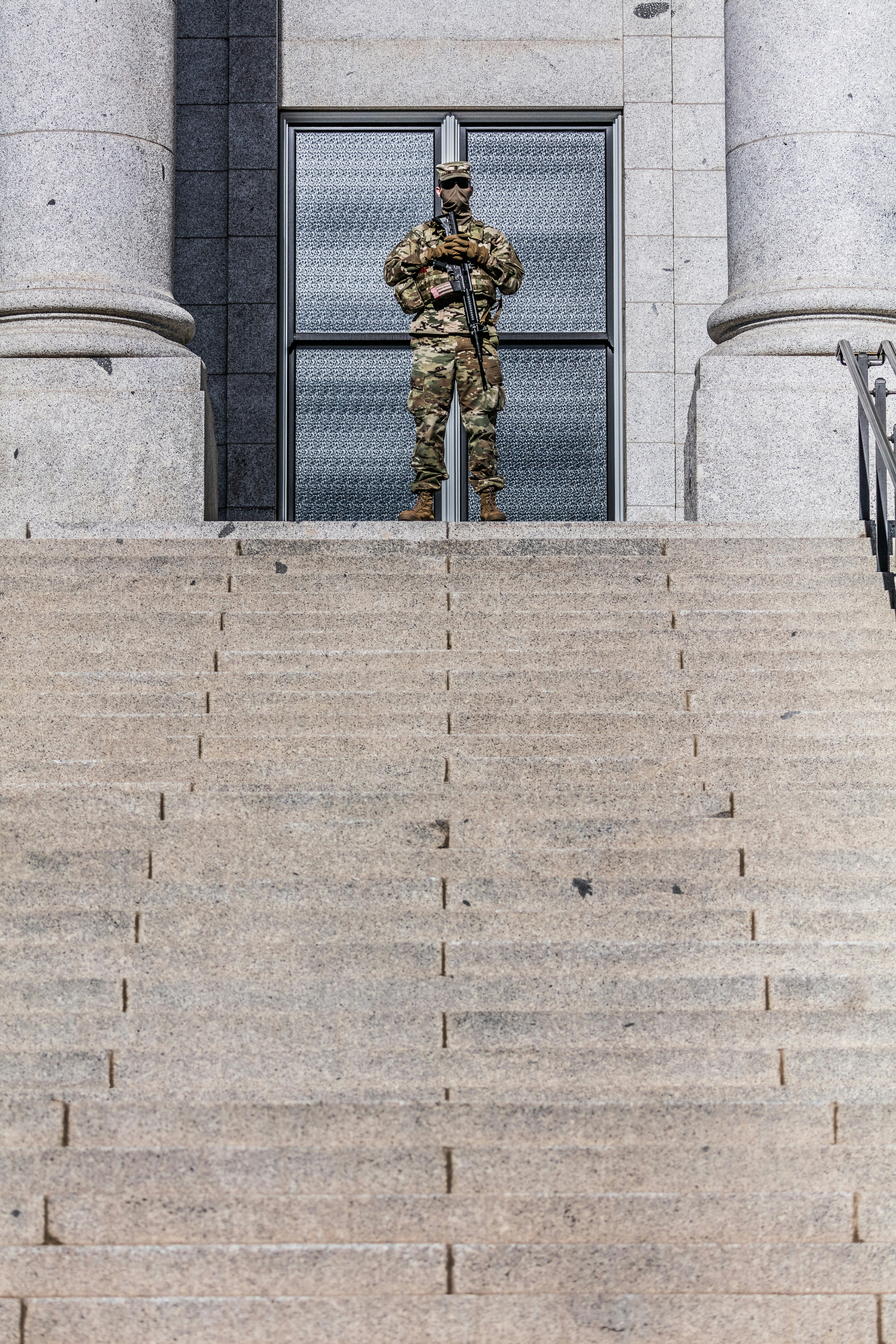 Sentinel at Civic Threshold: A Soldier Stands Guard on Stone Steps