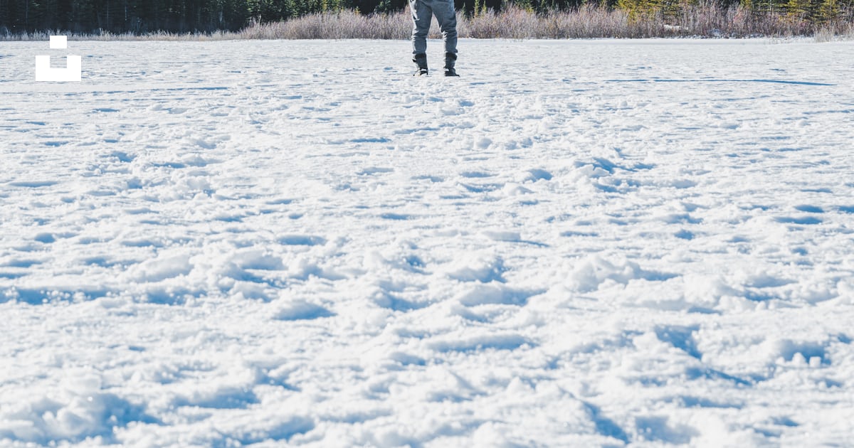 昼間、雪に覆われた地面を歩く黒いジャケットと黒いズボンを着た人の写真 Unsplashのバンフの無料画像
