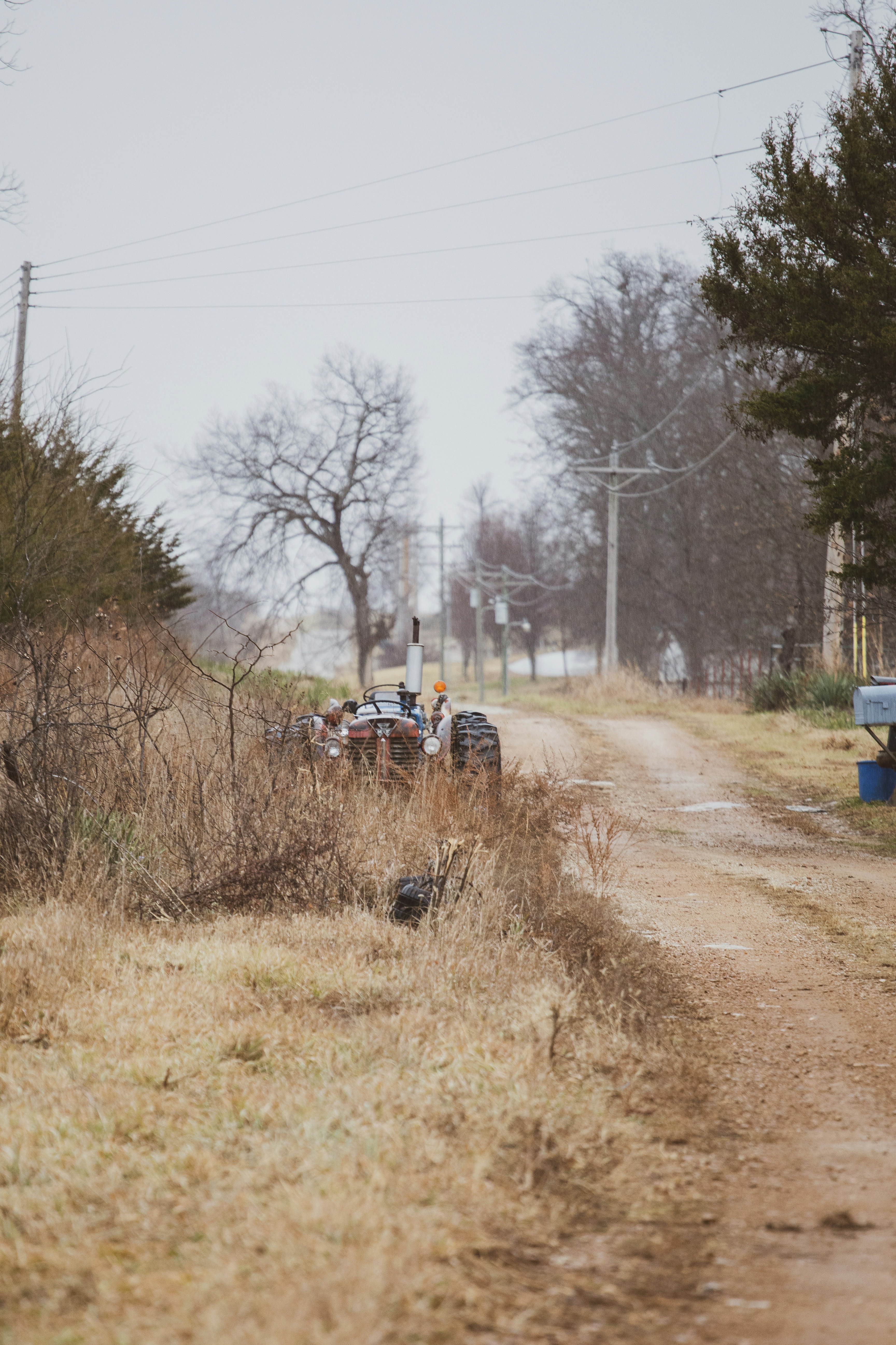 Dusty Rural Road with Vintage Tractor Silhouetted by Winter Light