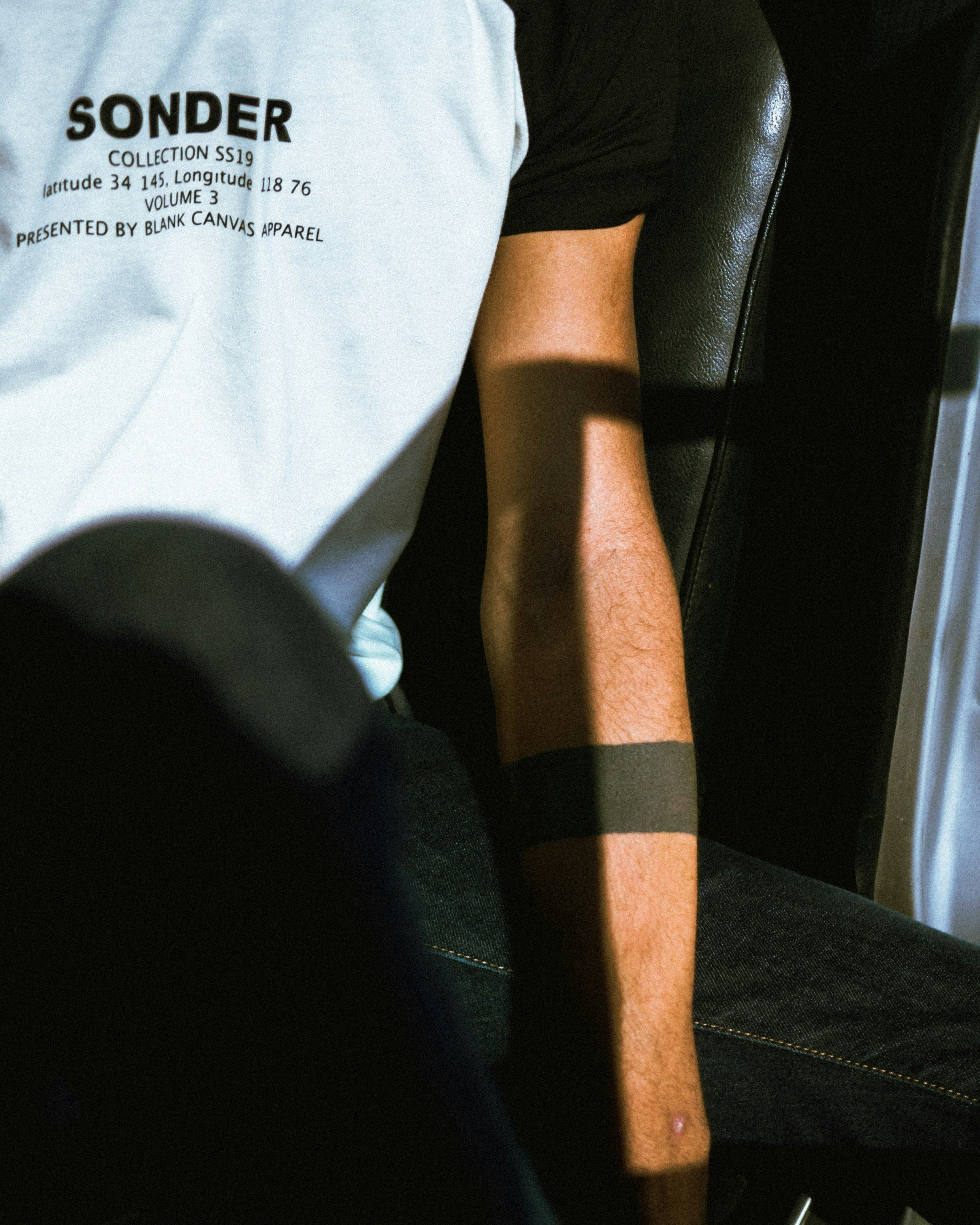 Stripes of Sunlight Across a SONDER Tee in a Car Portrait