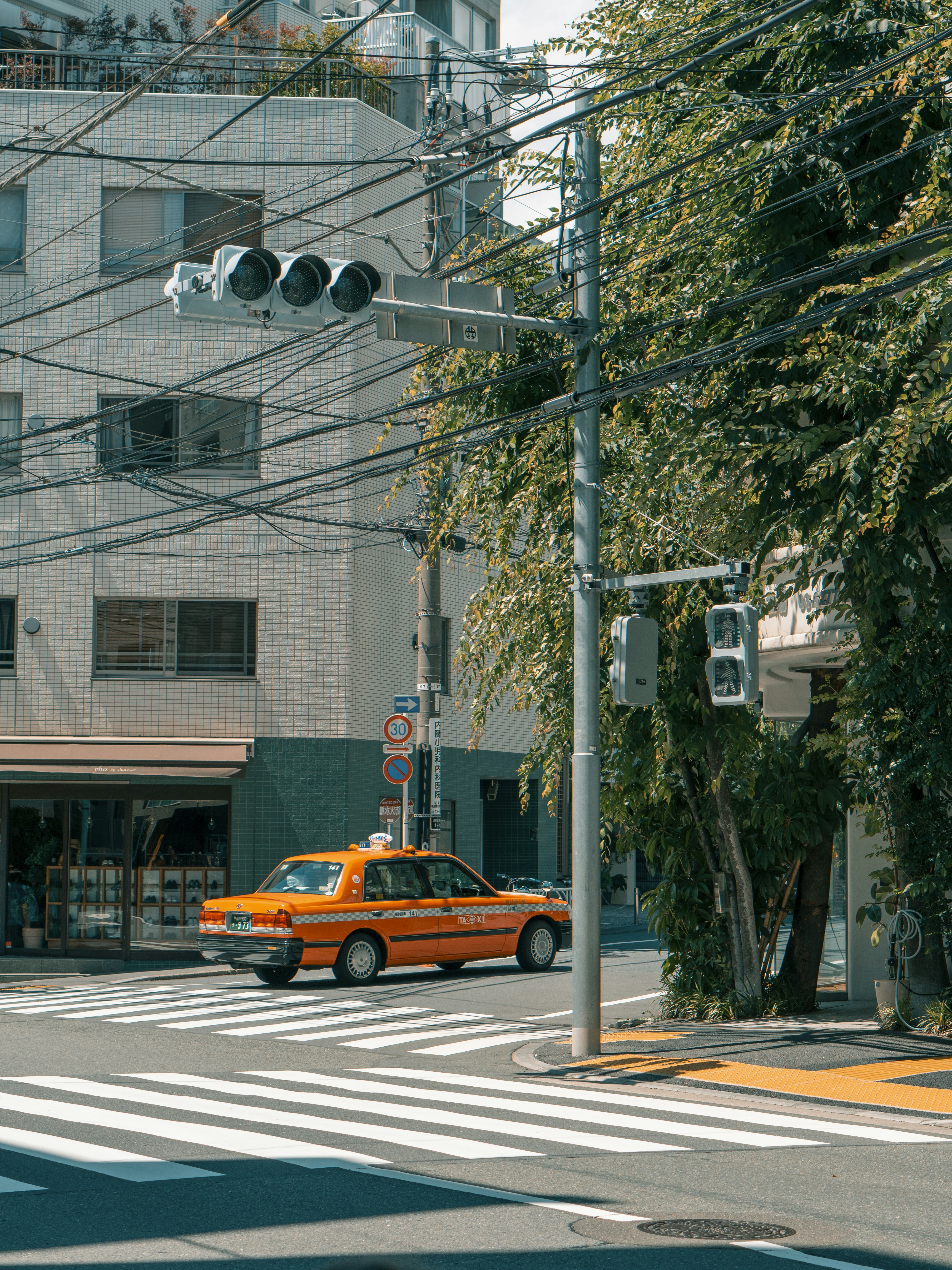 Yellow taxi navigating a busy intersection surrounded by urban architecture and tangled power lines.