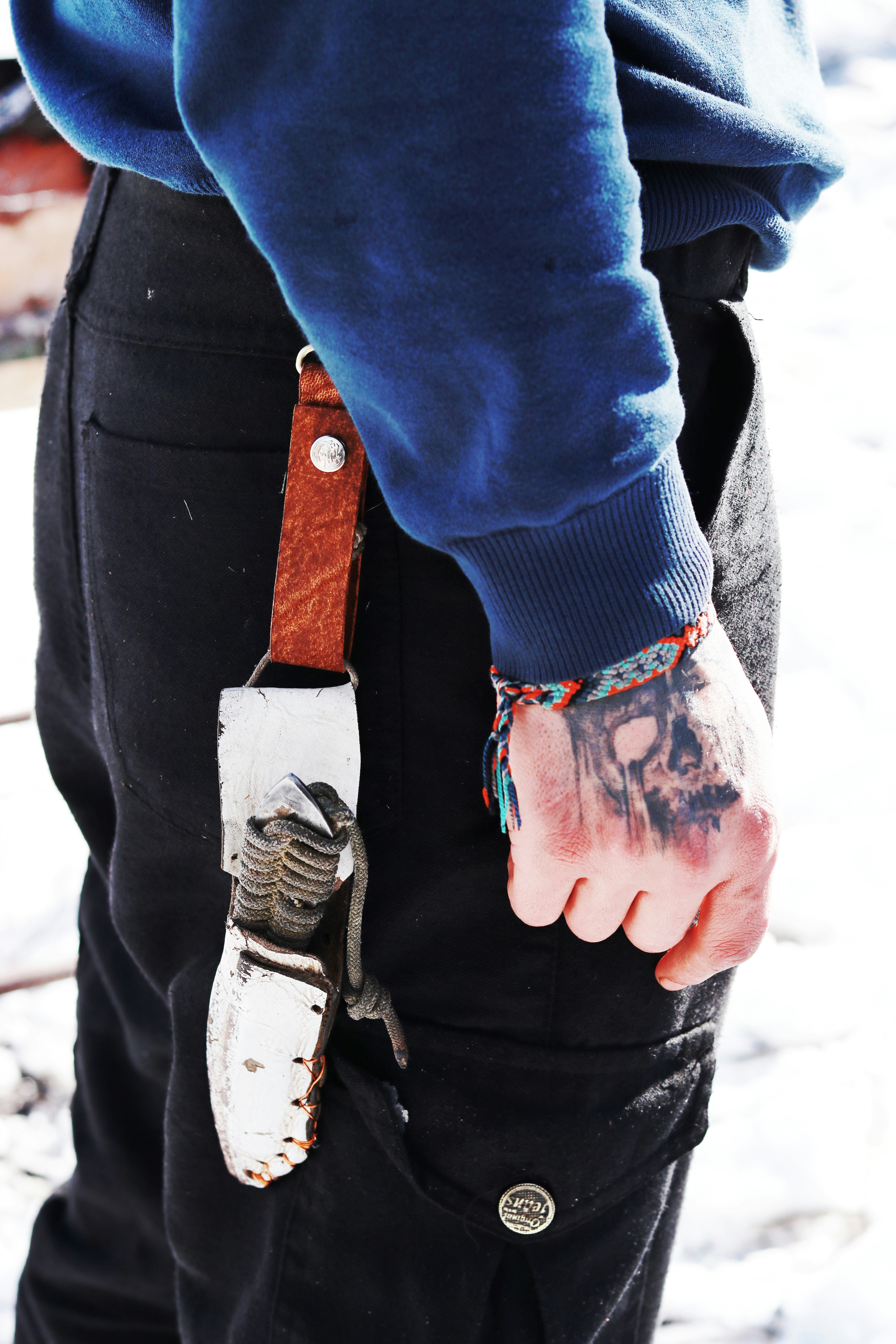 Grip in the Snow: leather sheath and tattooed hand