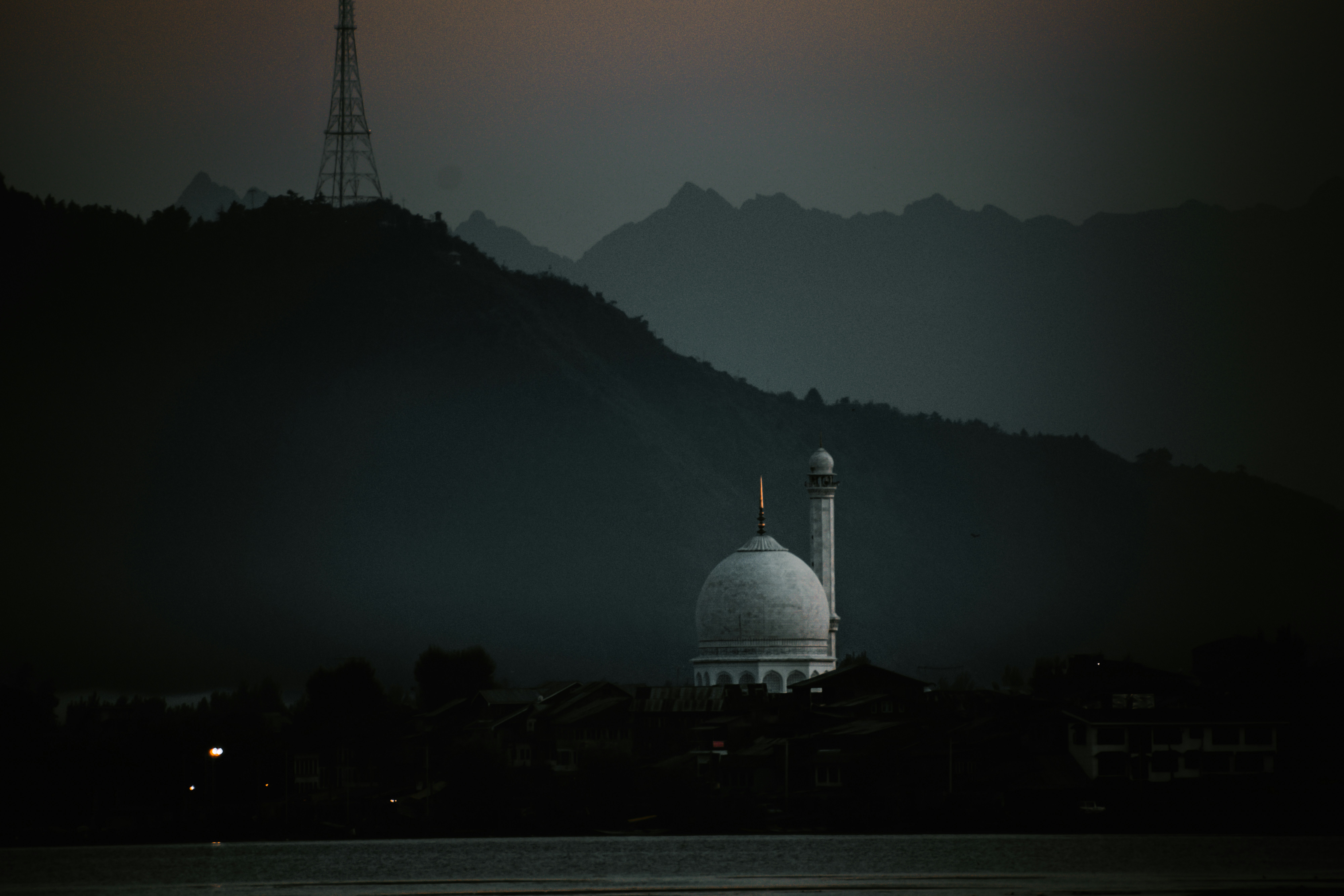 White dome building nestled against a mountainous backdrop during a foggy, twilight setting.