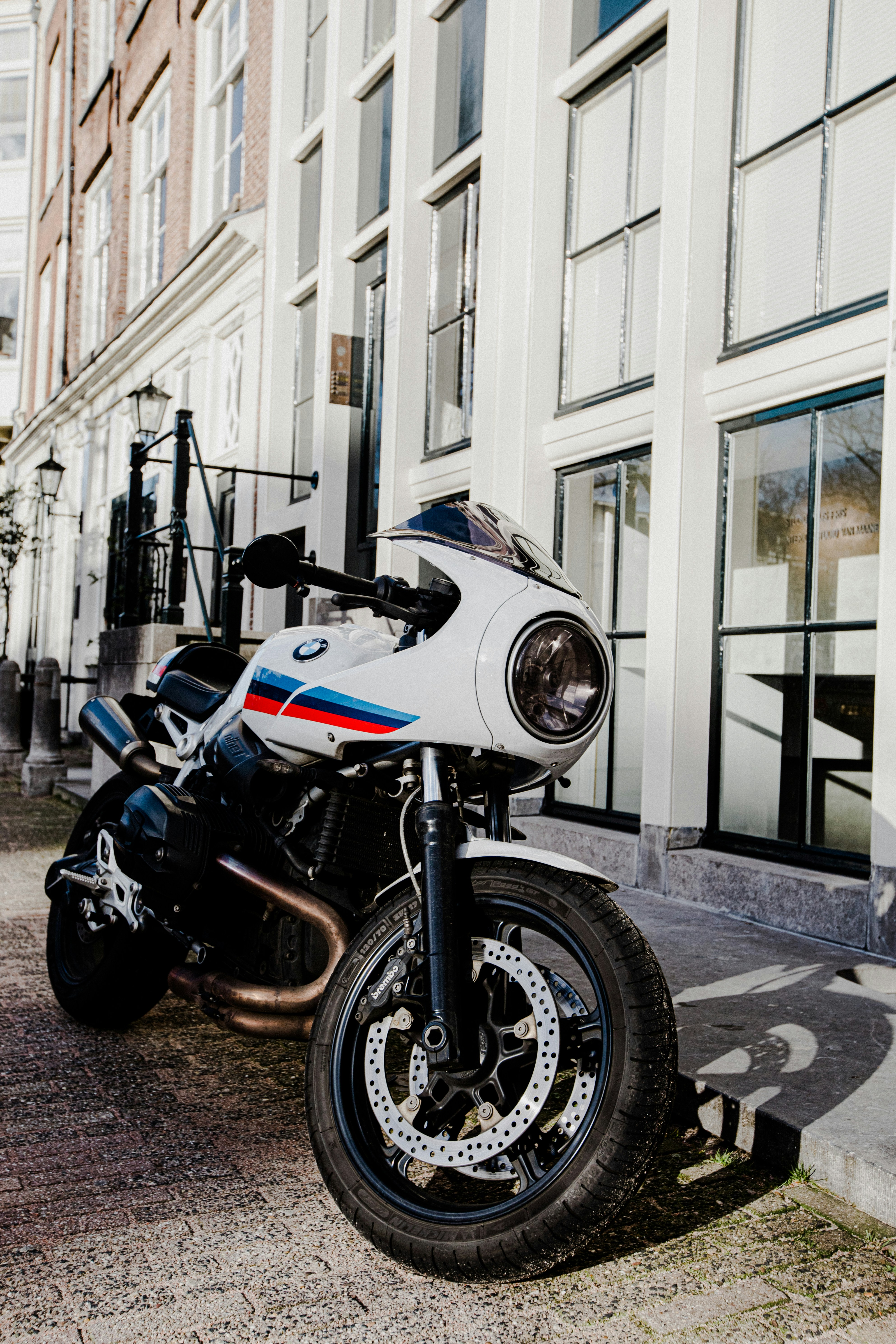 Chrome on Concrete: White BMW Café Racer Pauses by a Glass-Fronted Facade