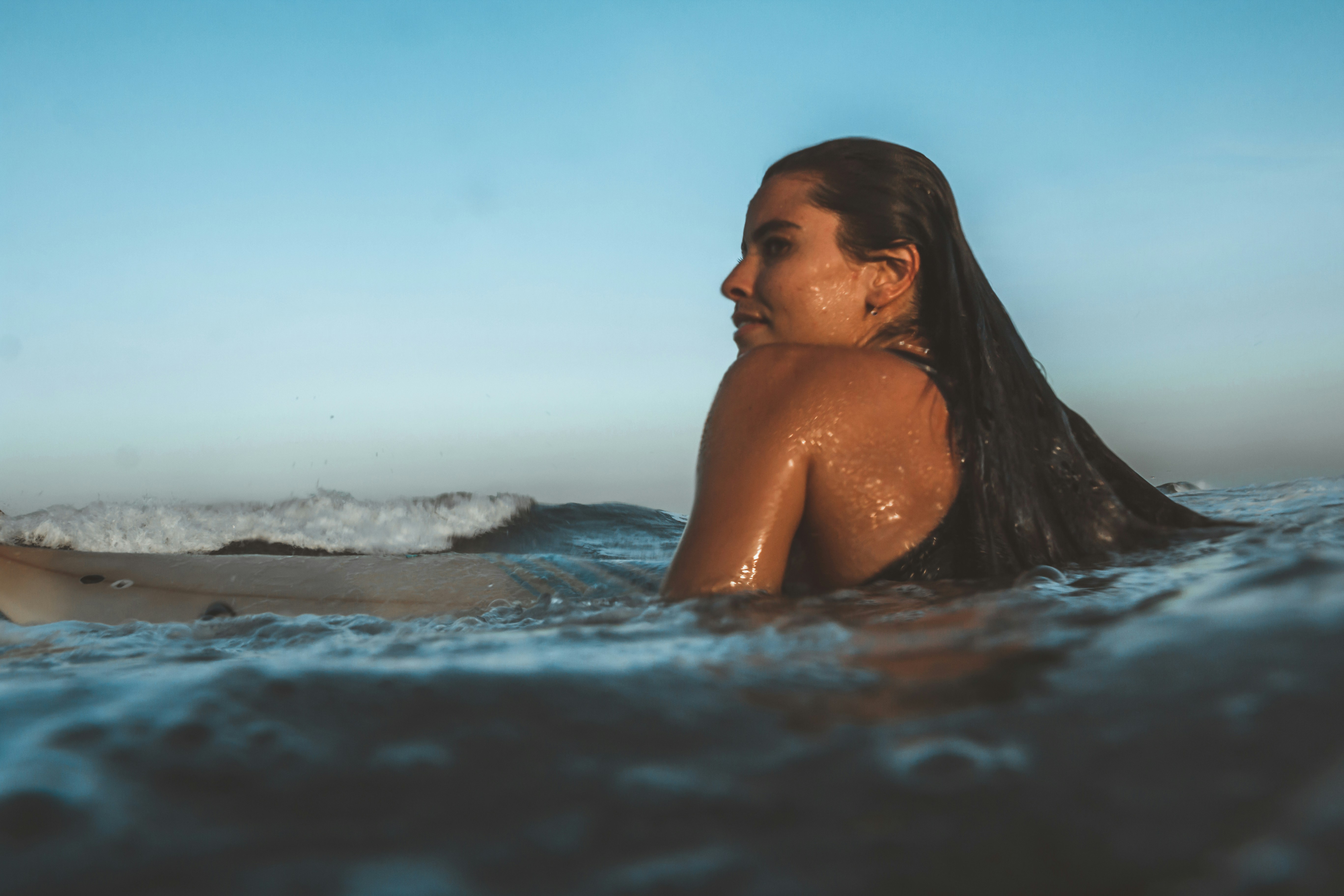 Person immersed in ocean waves with a gentle sunrise in the background.