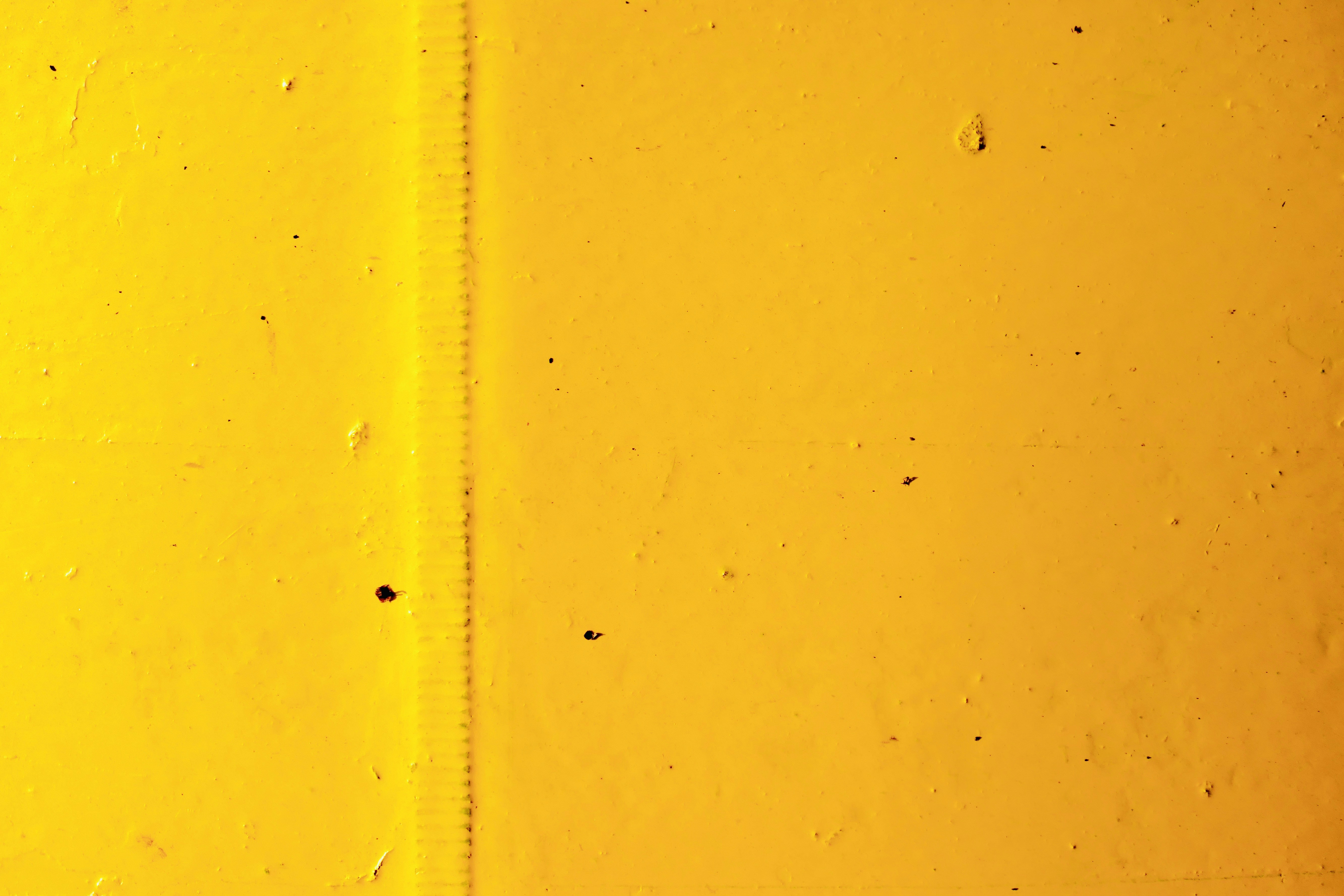 Close-up of a textured yellow surface, revealing subtle imperfections and variations in color. Ideal for exploring color theory and material properties.