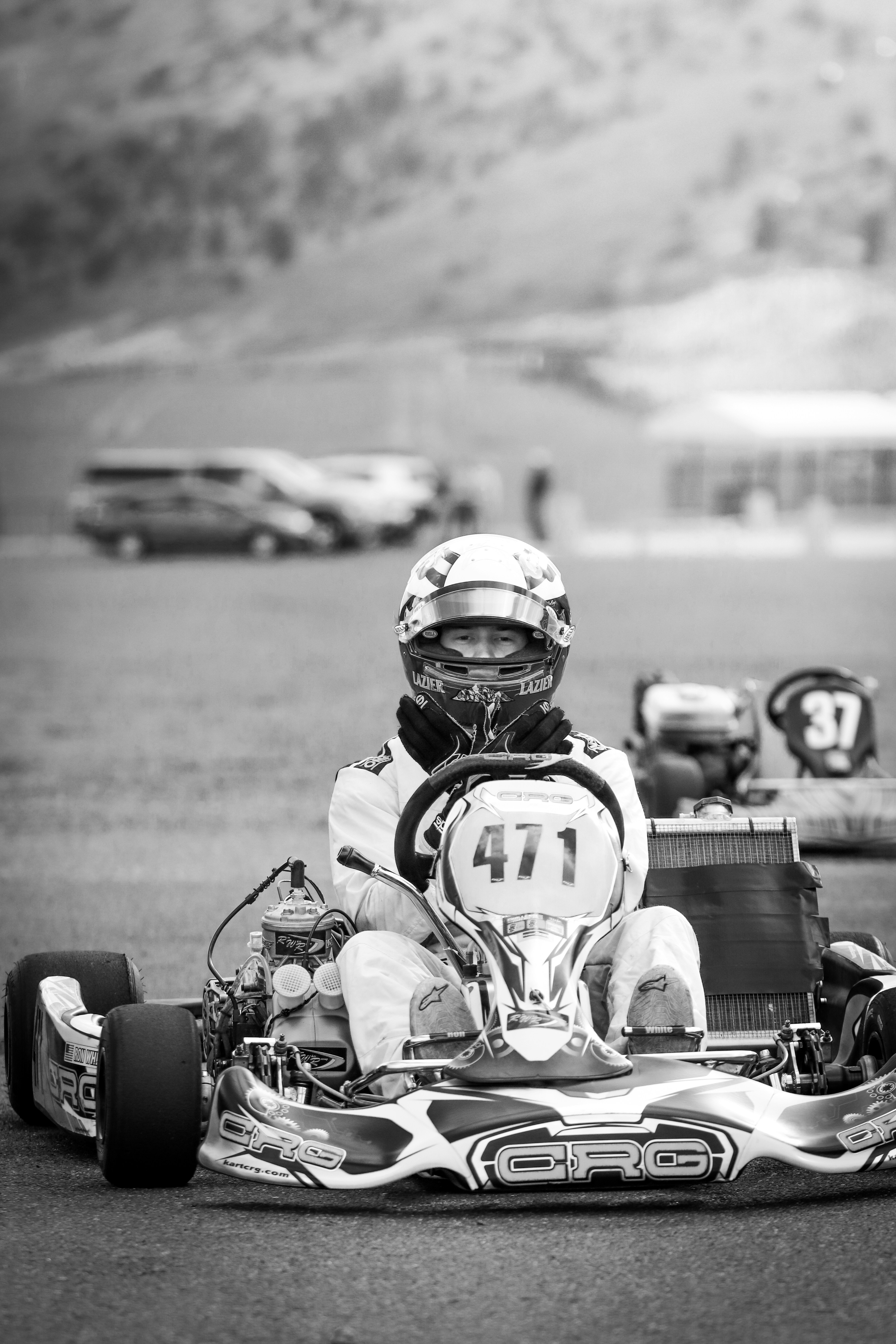 Grayscale photo of a go-kart driver wearing a helmet, poised for action on the track.
