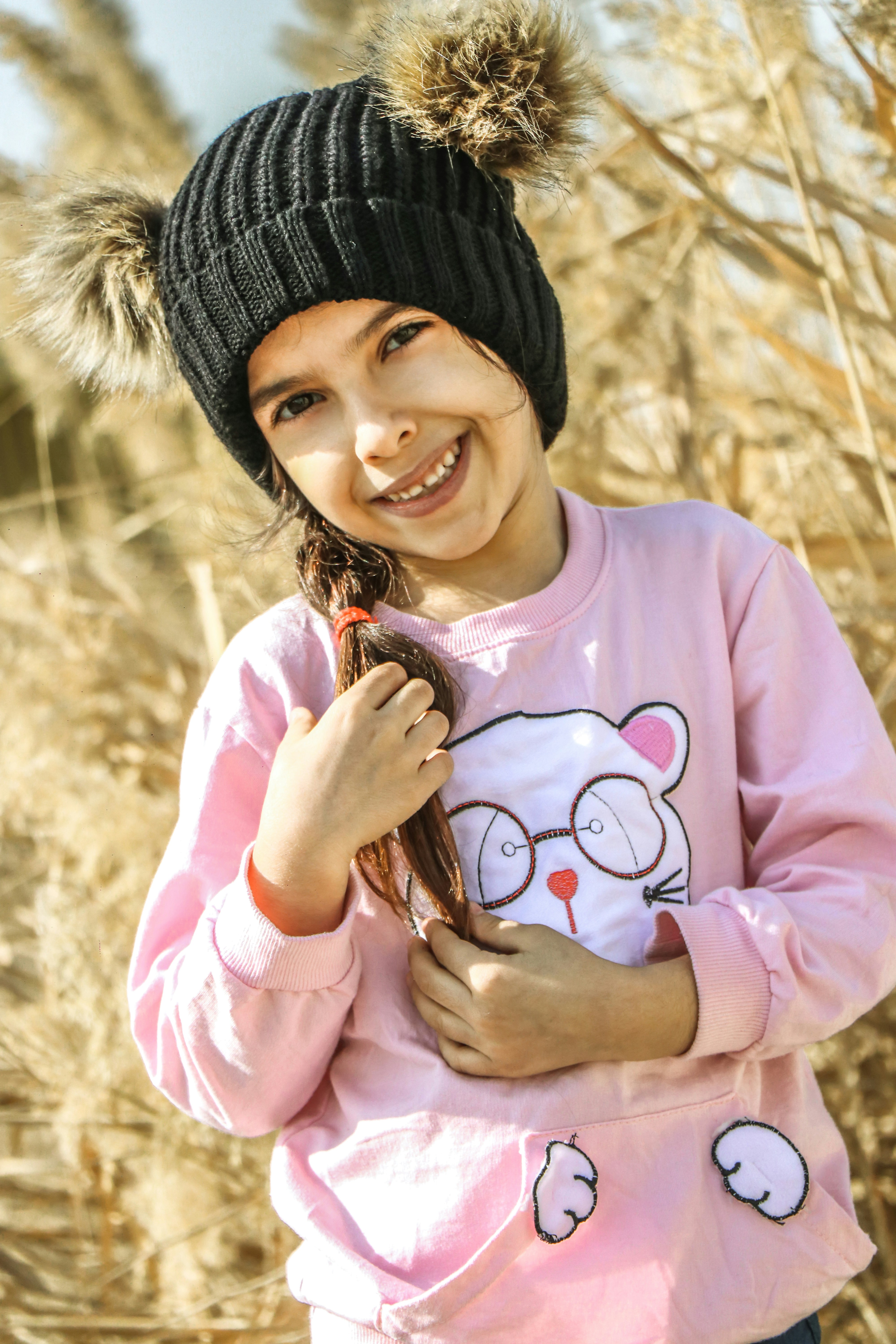 girl in pink long sleeve shirt and black knit cap smiling