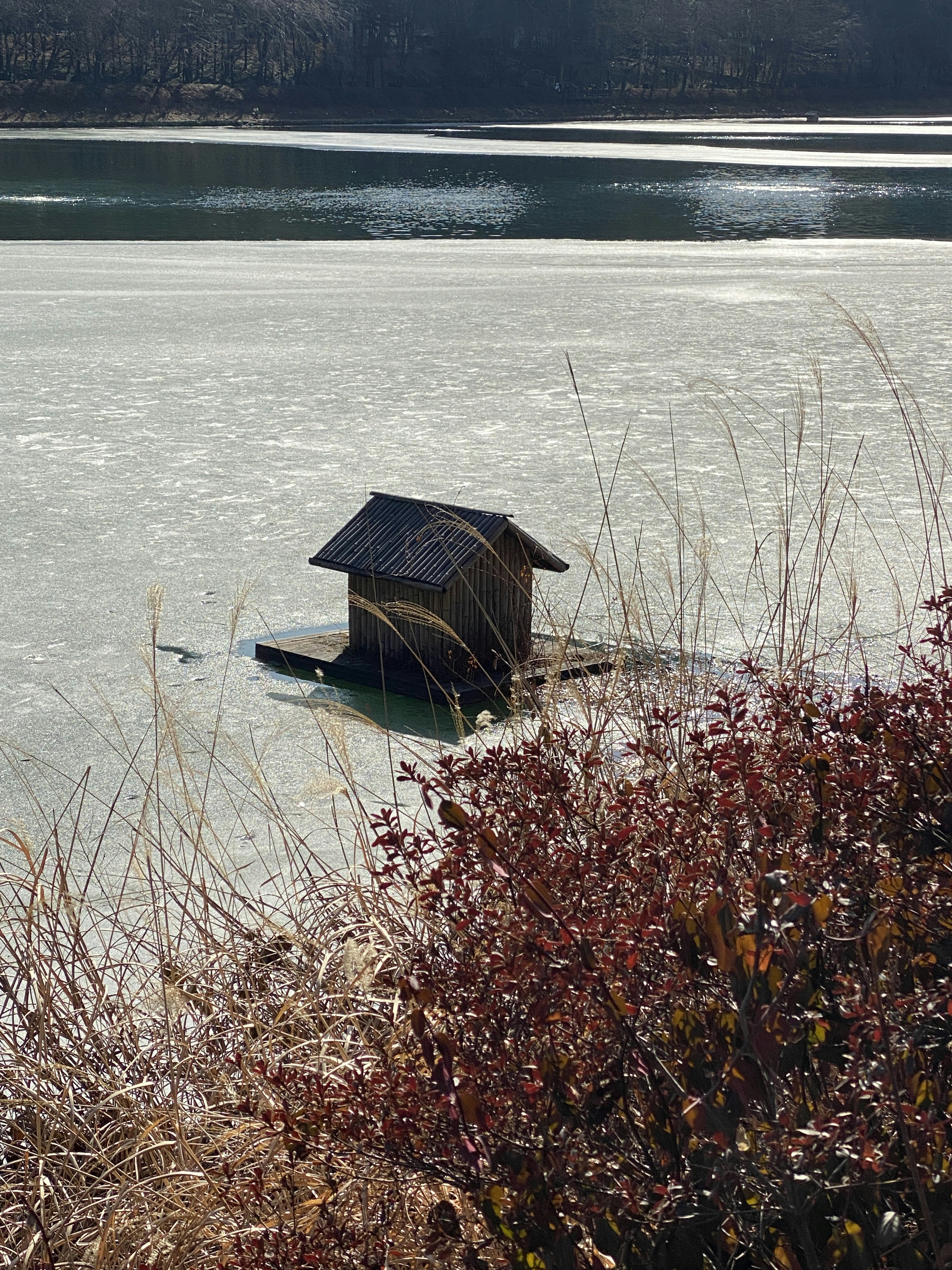 A lone boathouse anchored on a thin ice-domed lake