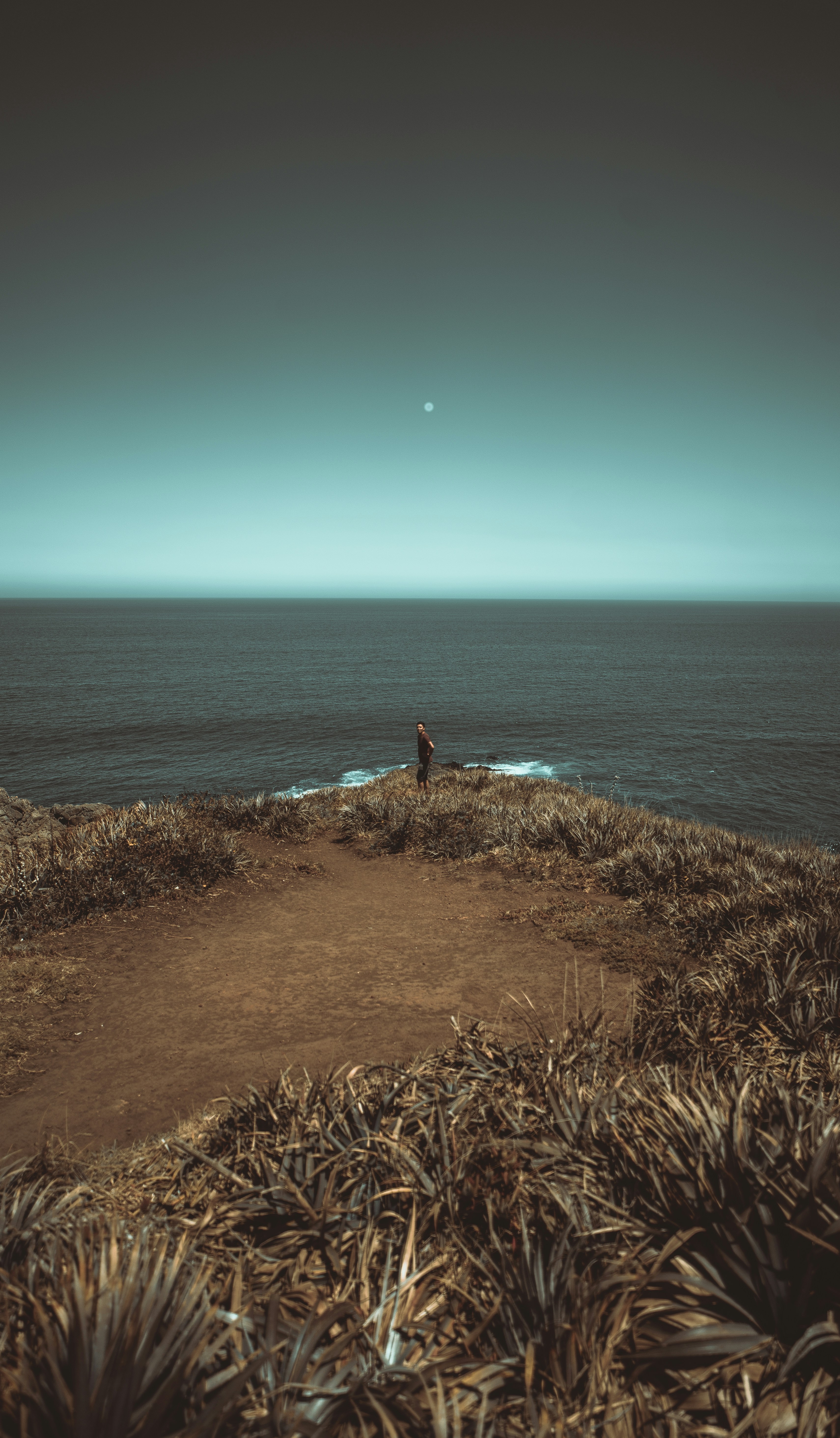 Waypoint at the Edge: solitary figure gazing at a turquoise horizon