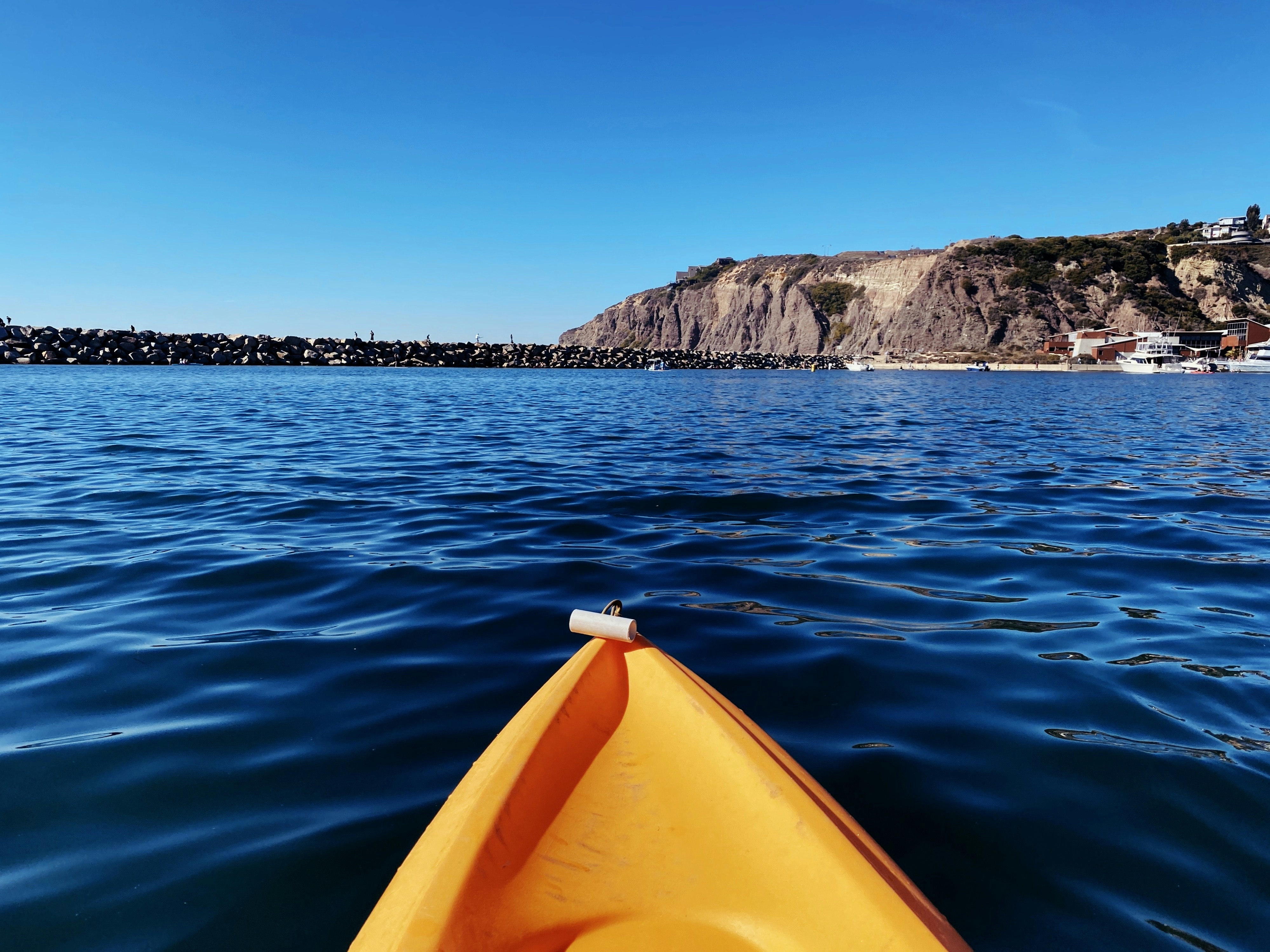 Kayak jaune sur la mer bleue près de la montagne brune et verte sous le ...